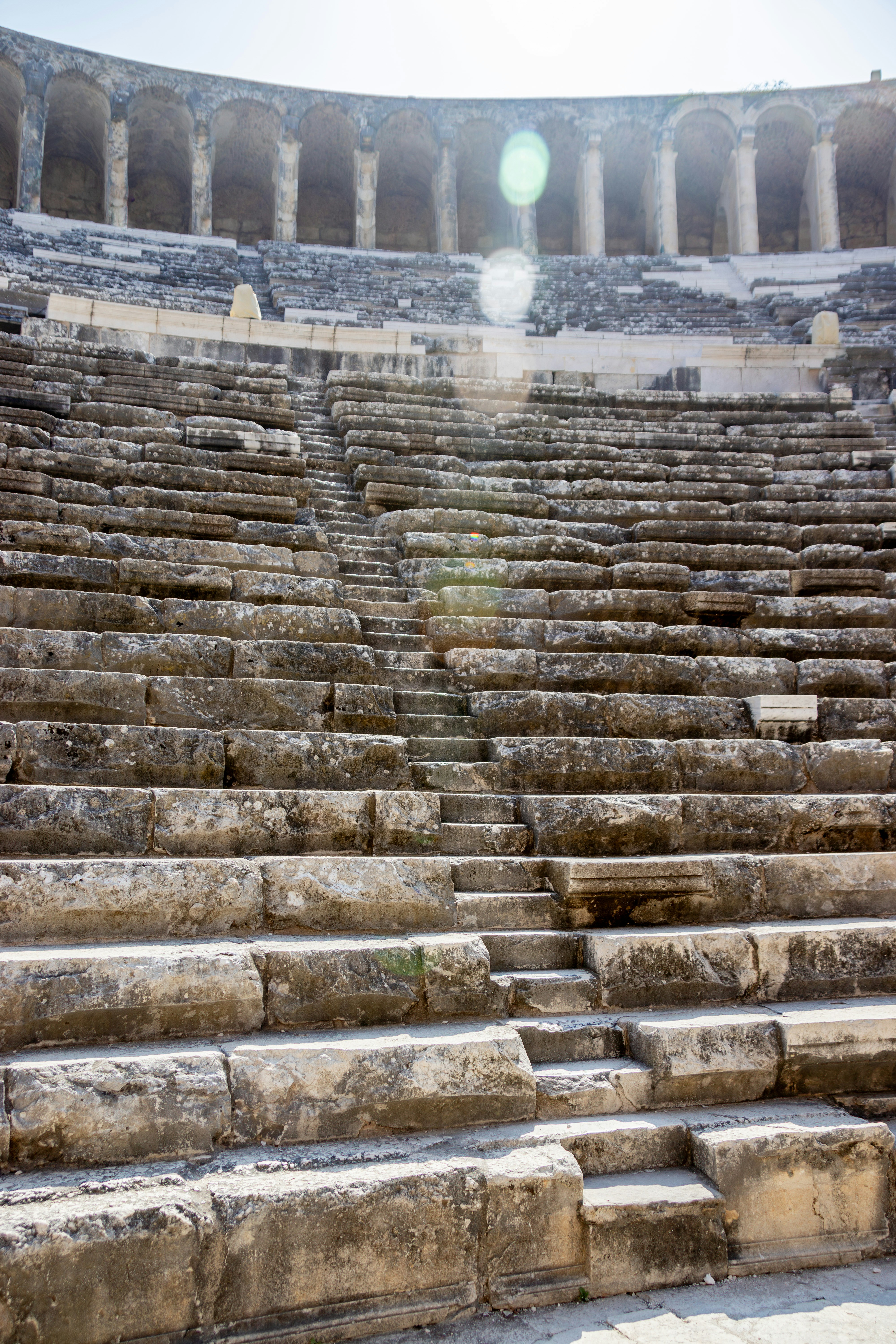 Stone steps of an ancient amphitheater leading towards the upper tiers, showcasing the architectural grandeur and historical significance of the venue.
