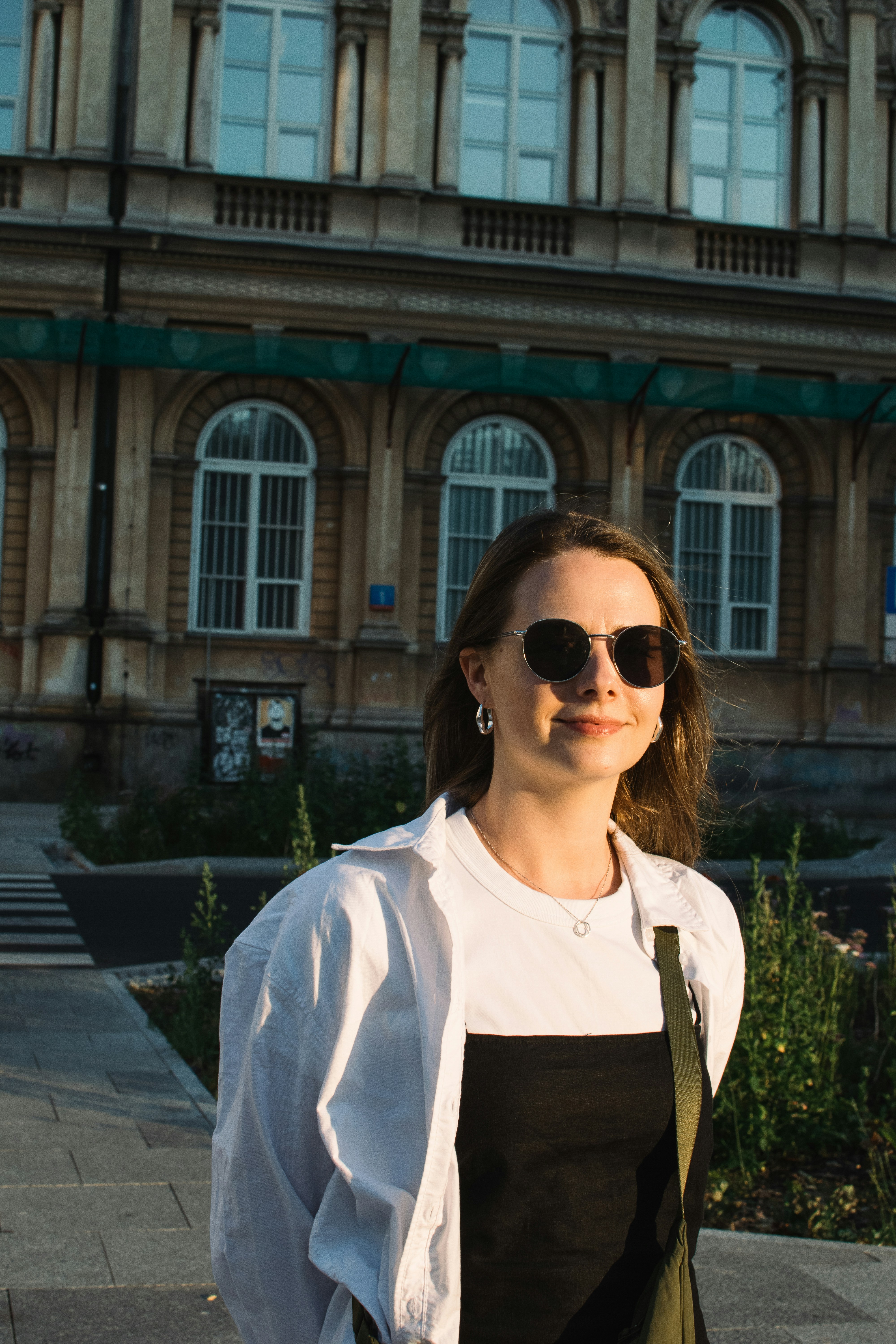 Woman smiles for the camera in front of a building.