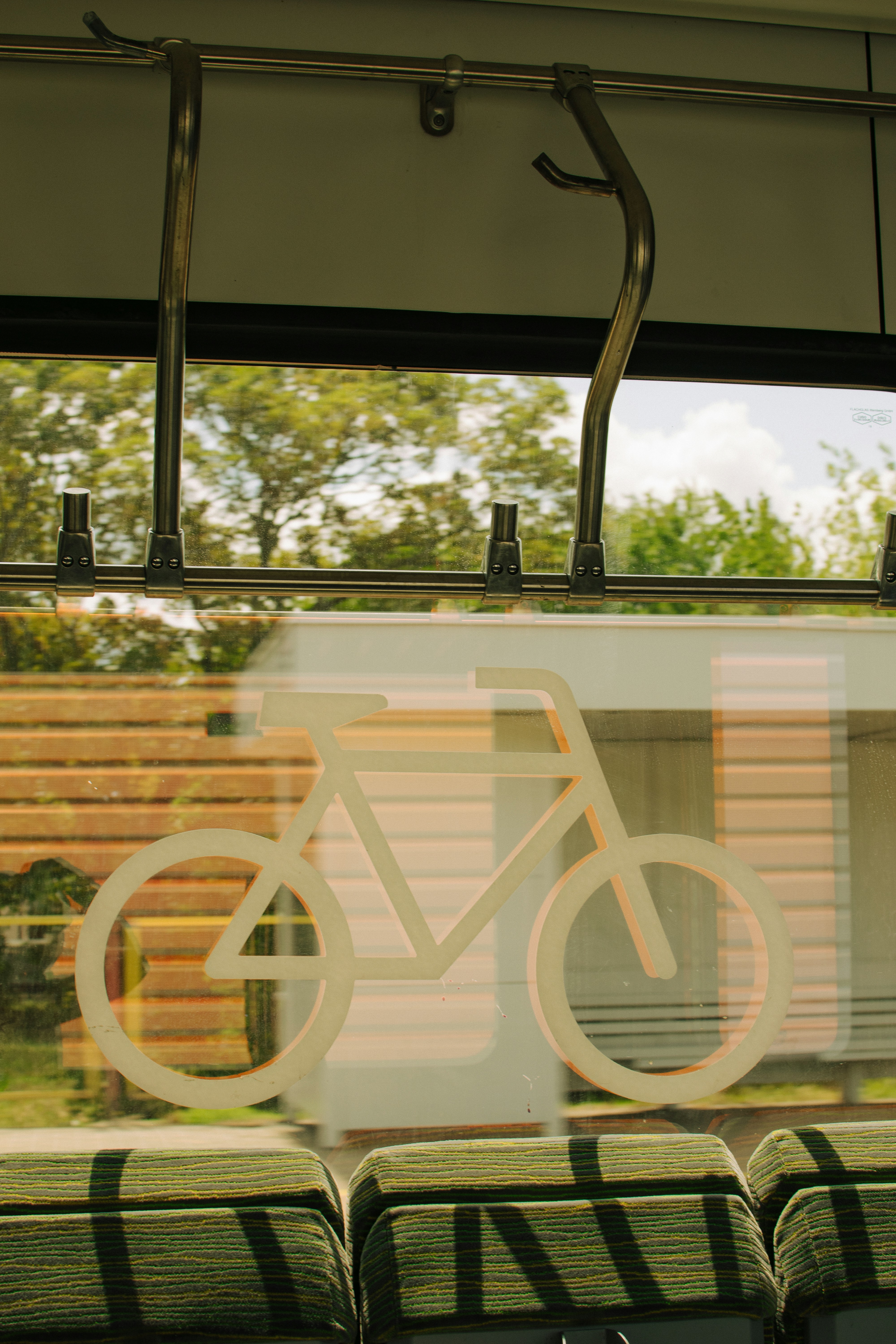 Translucent bicycle logo on a bus window, framed by the interior seating and the blurred outdoor landscape.