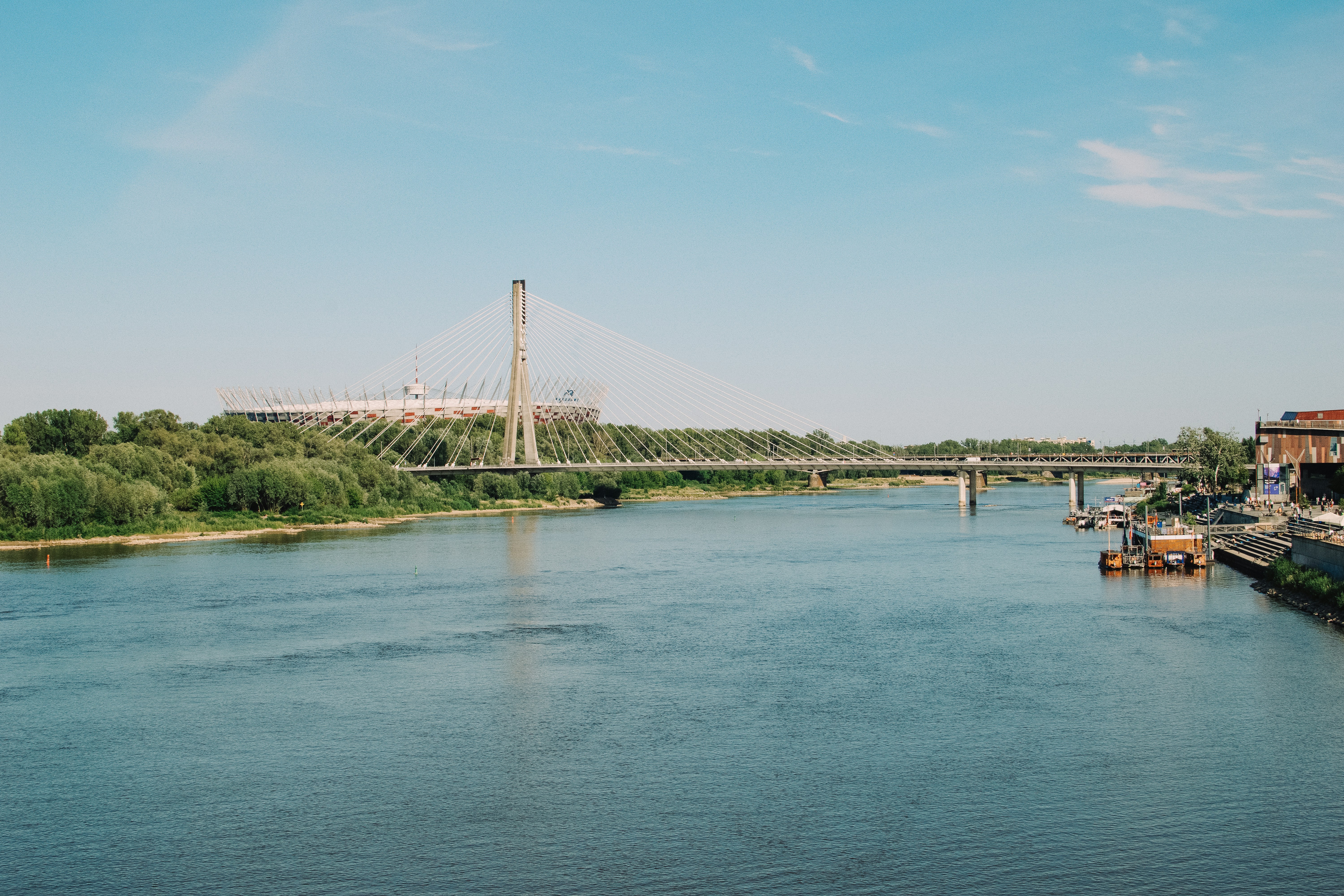 A bridge spans a wide river under a blue sky.