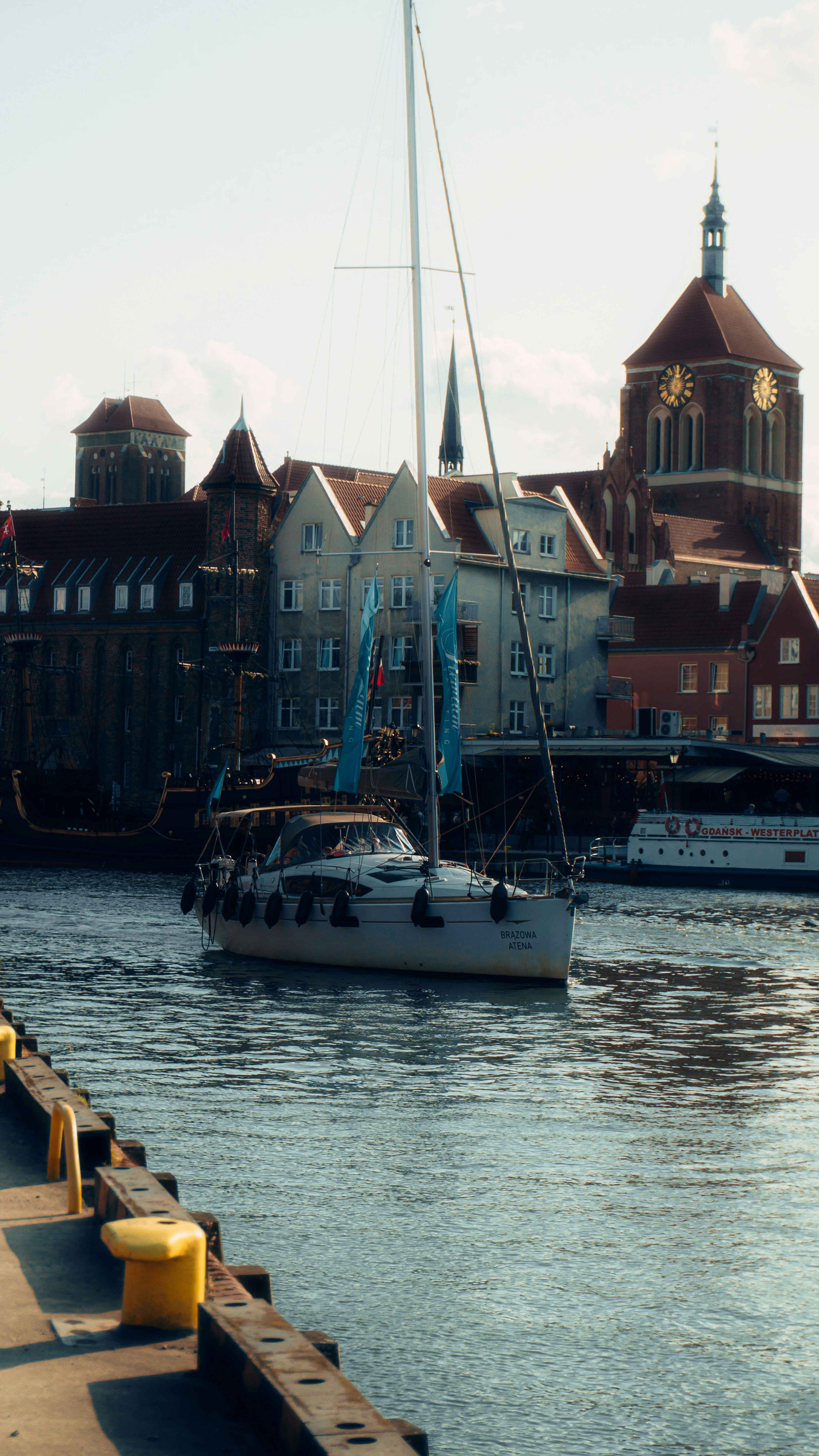 A sailboat glides in front of a historic city.