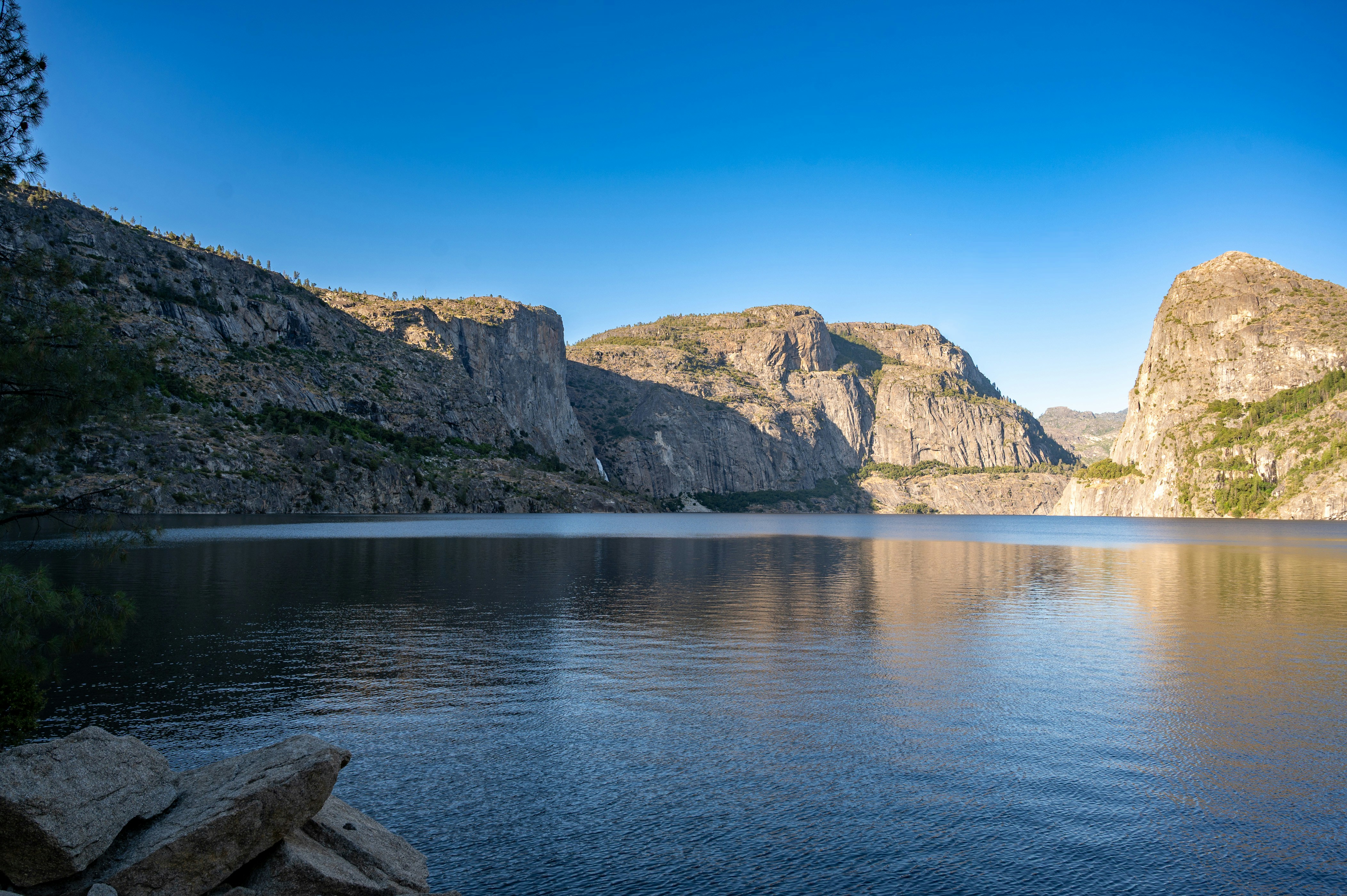 Sunlit Cliffs Framing a Tranquil Cove under a Clear Blue Sky
