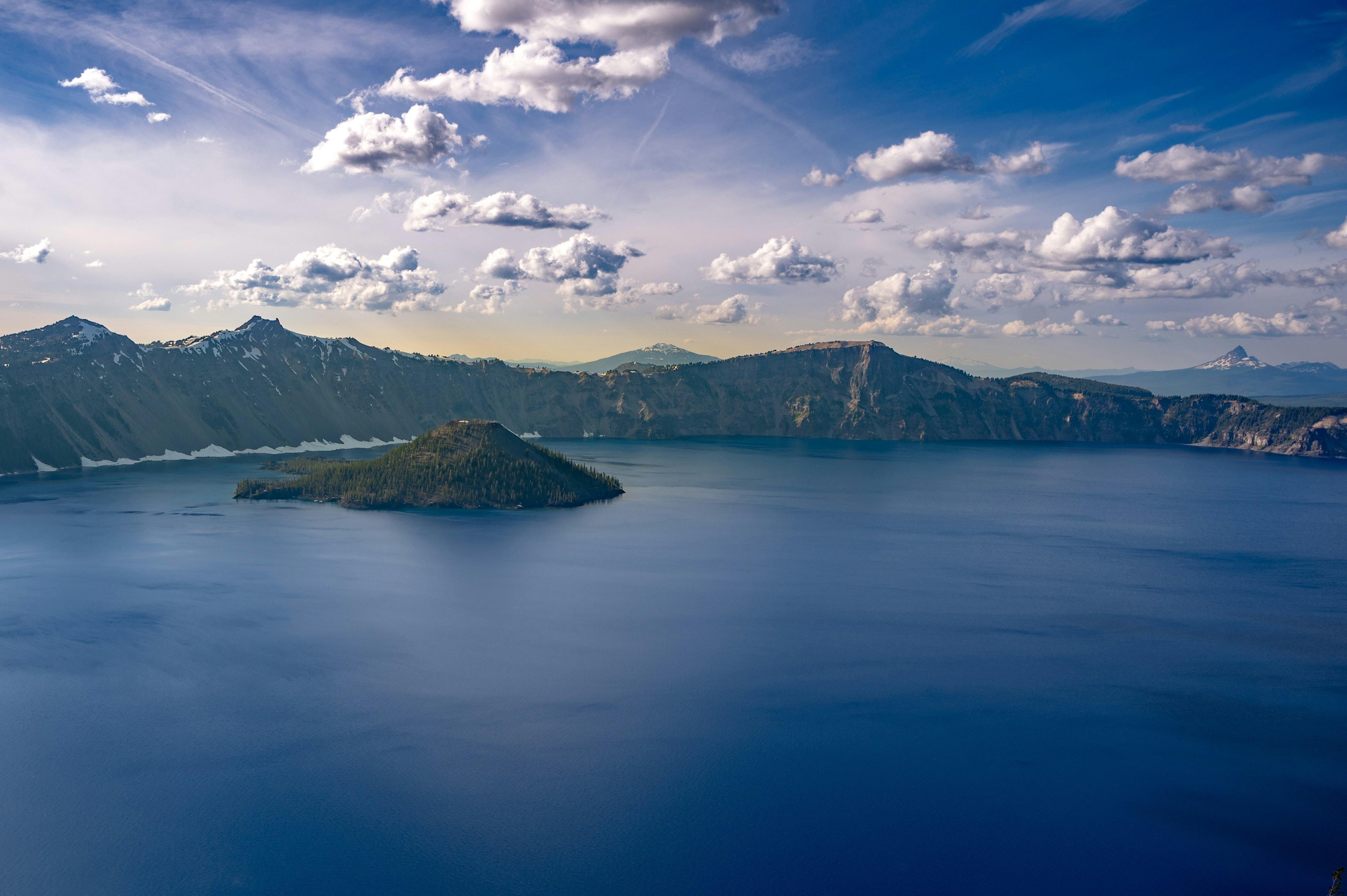 Vast lake surrounded by mountains under a blue sky.