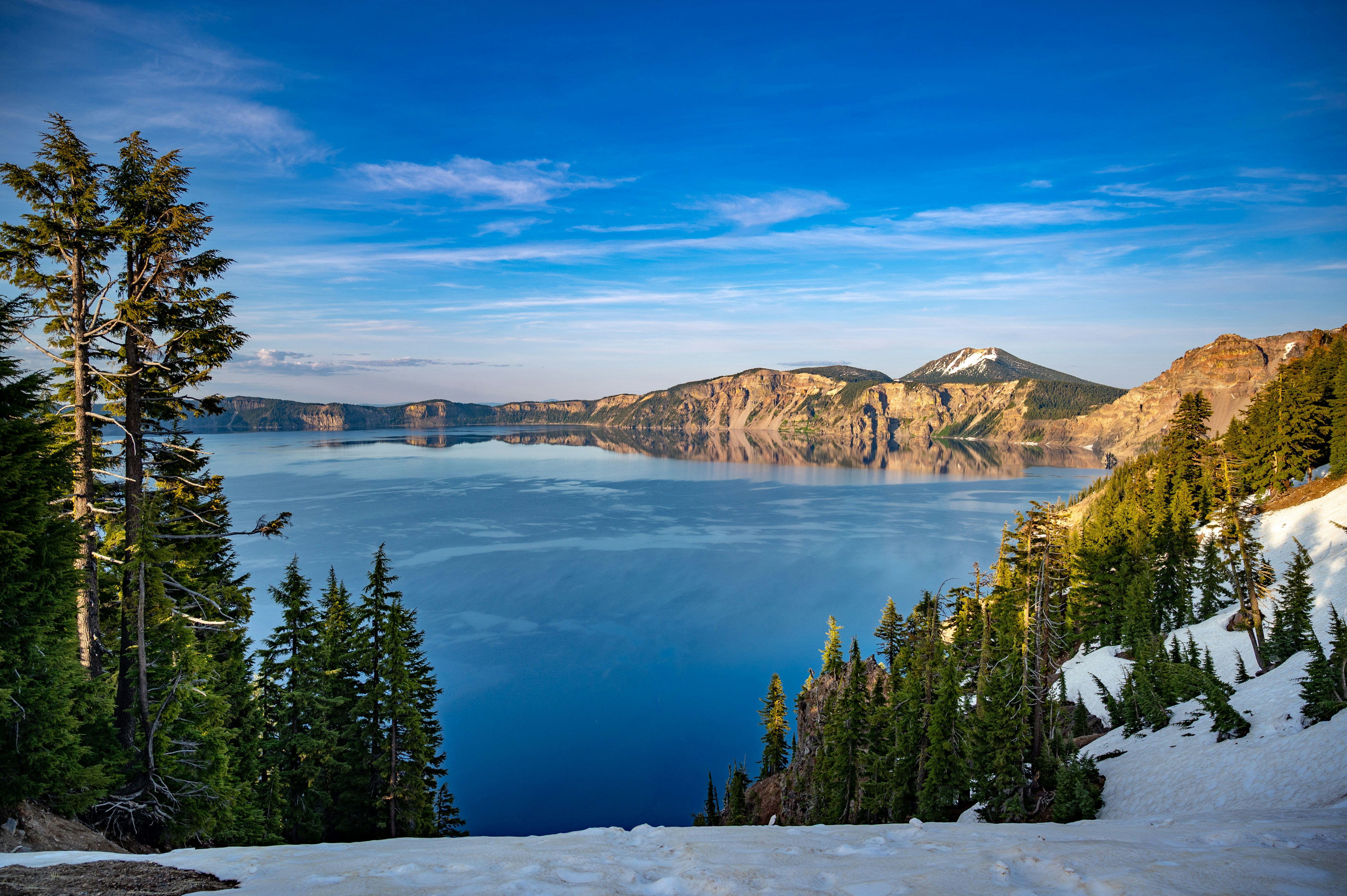 Rim of Silence: Snow-Kissed Pines Frame the Glacier-Blue Crater Lake