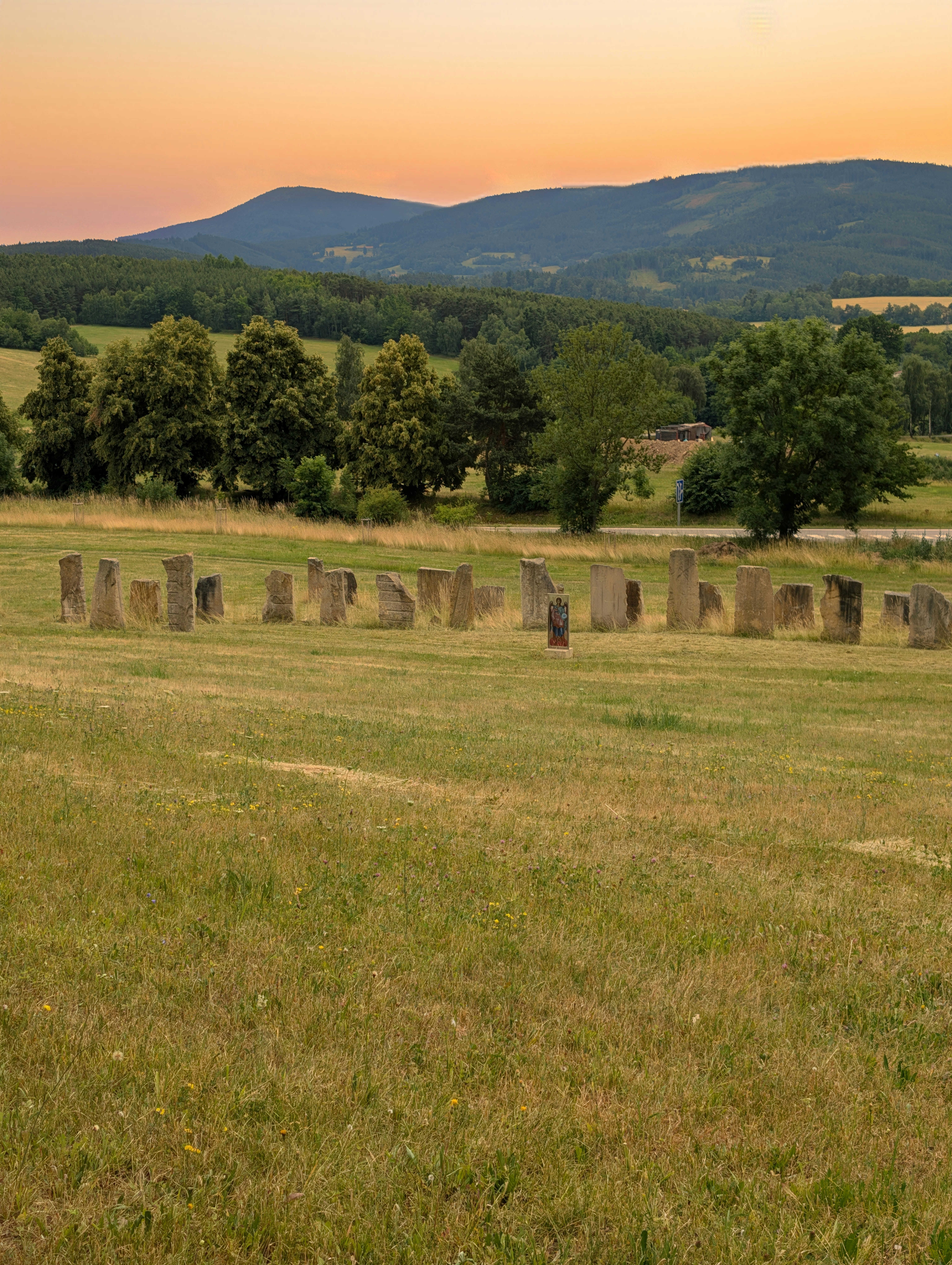 A stone circle stands in a field at sunset.