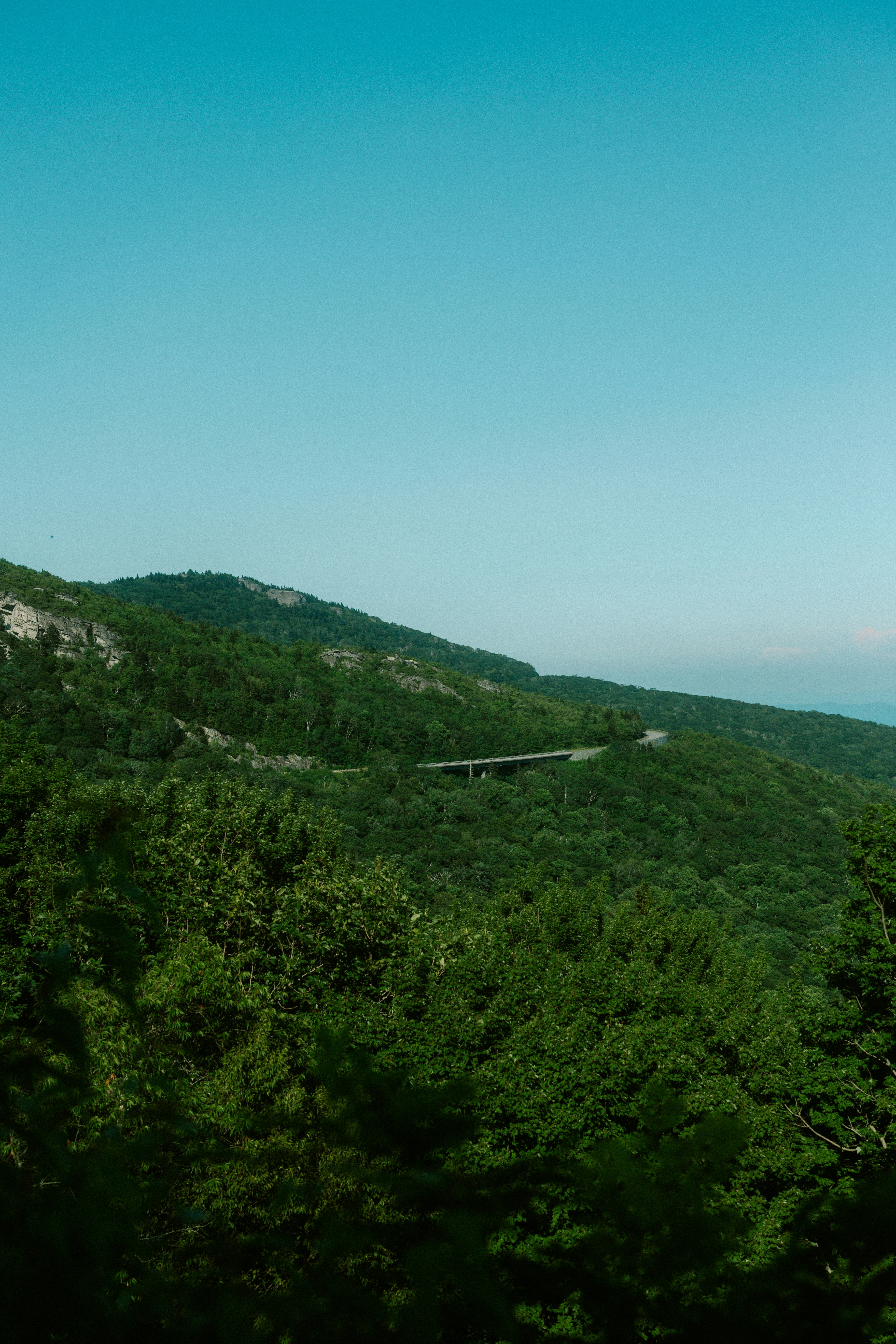 Green mountains stand under a bright blue sky.