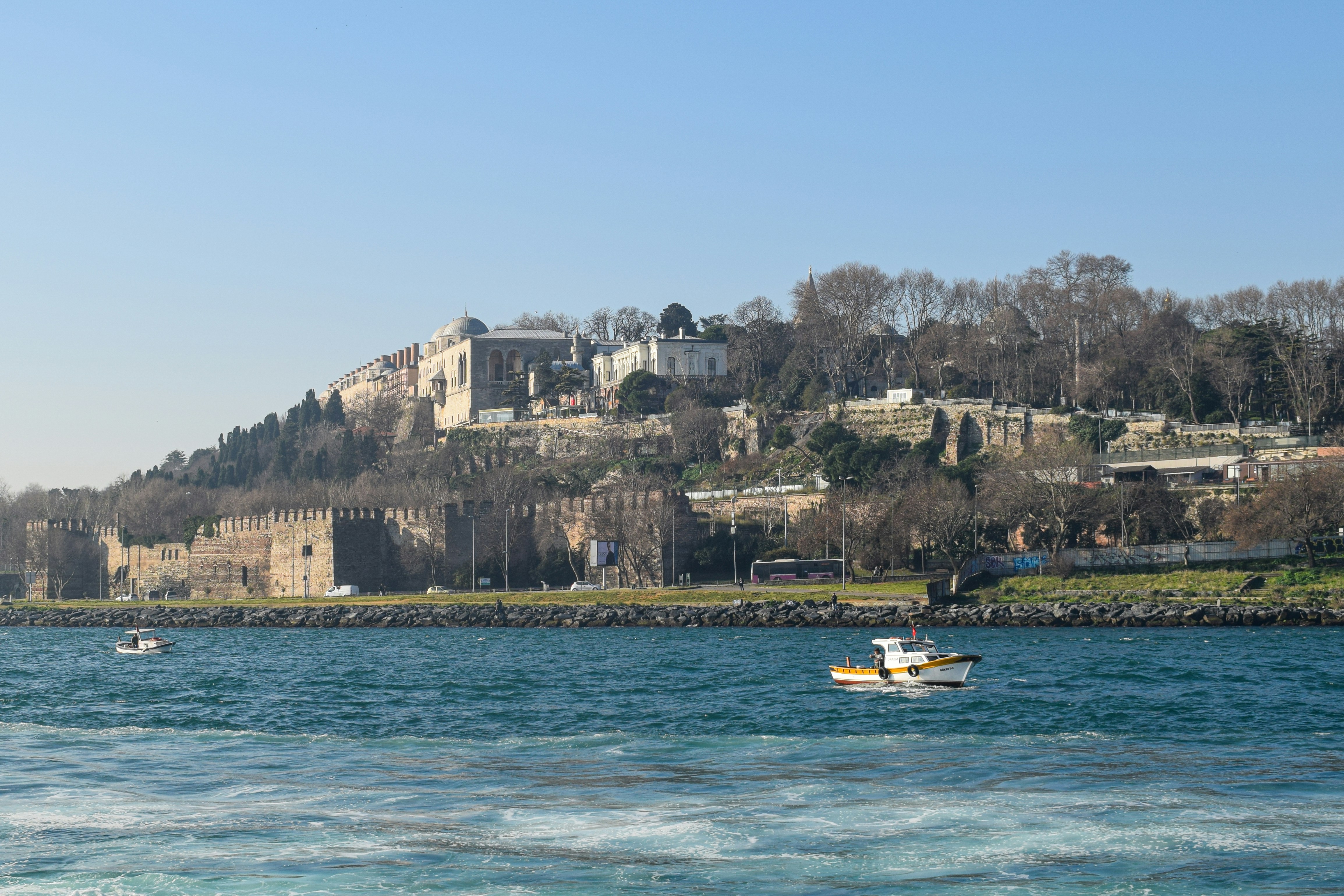 Topkapi Palace and the old city walls seen from the Bosphorus in Istanbul. | A castle overlooking the bosphorus strait.