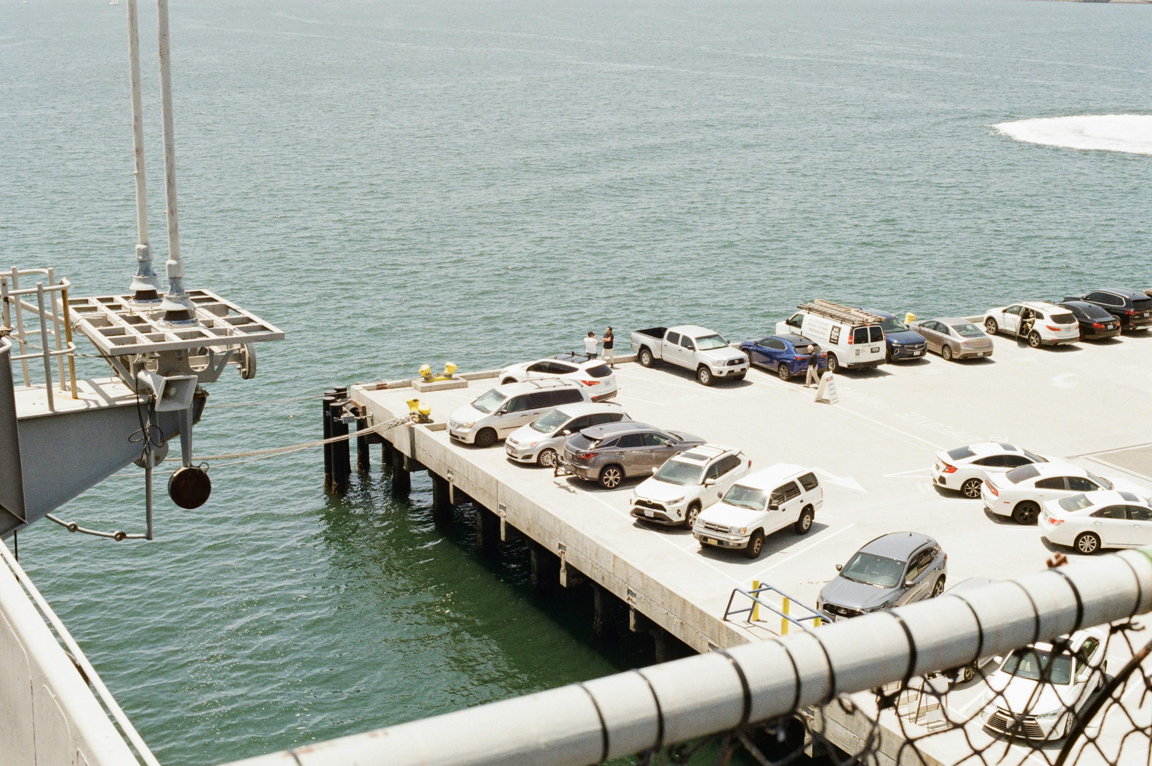 Cars are parked on a dock next to the water. photo – Free Harbor Image ...