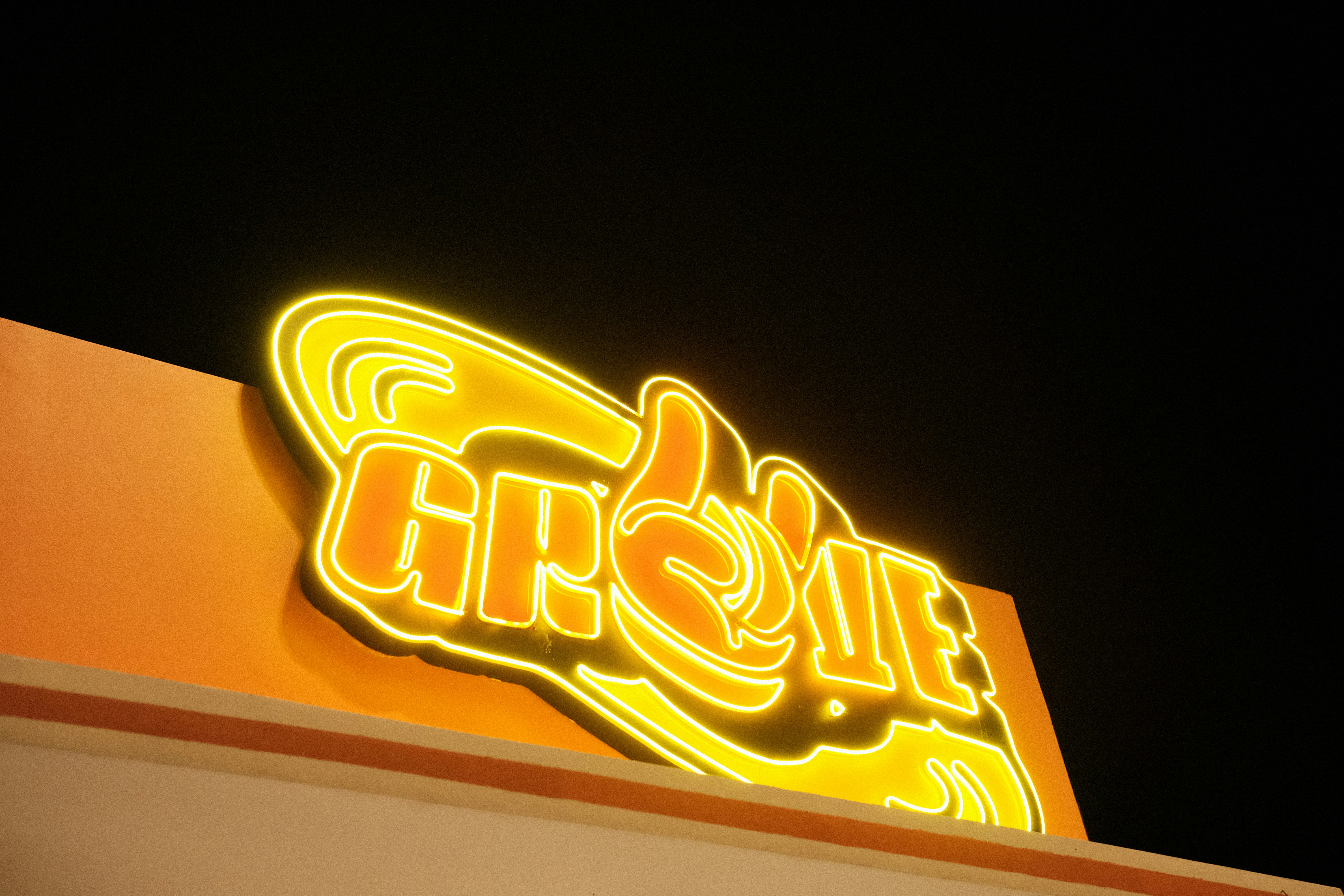 A glowing "groove" sign shines brightly at night. photo – Free Neon ...