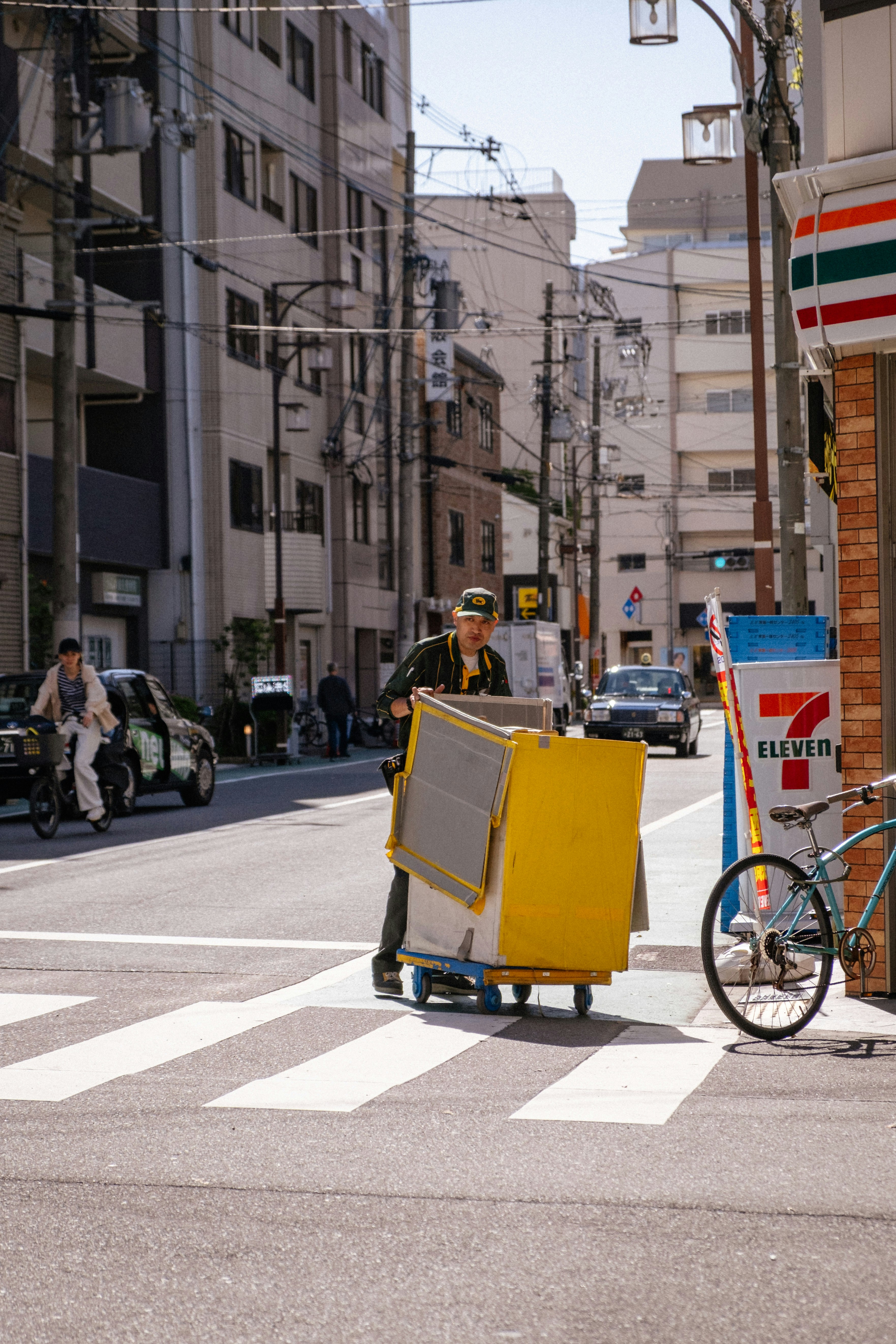 A person pushes a cart on a city street.
