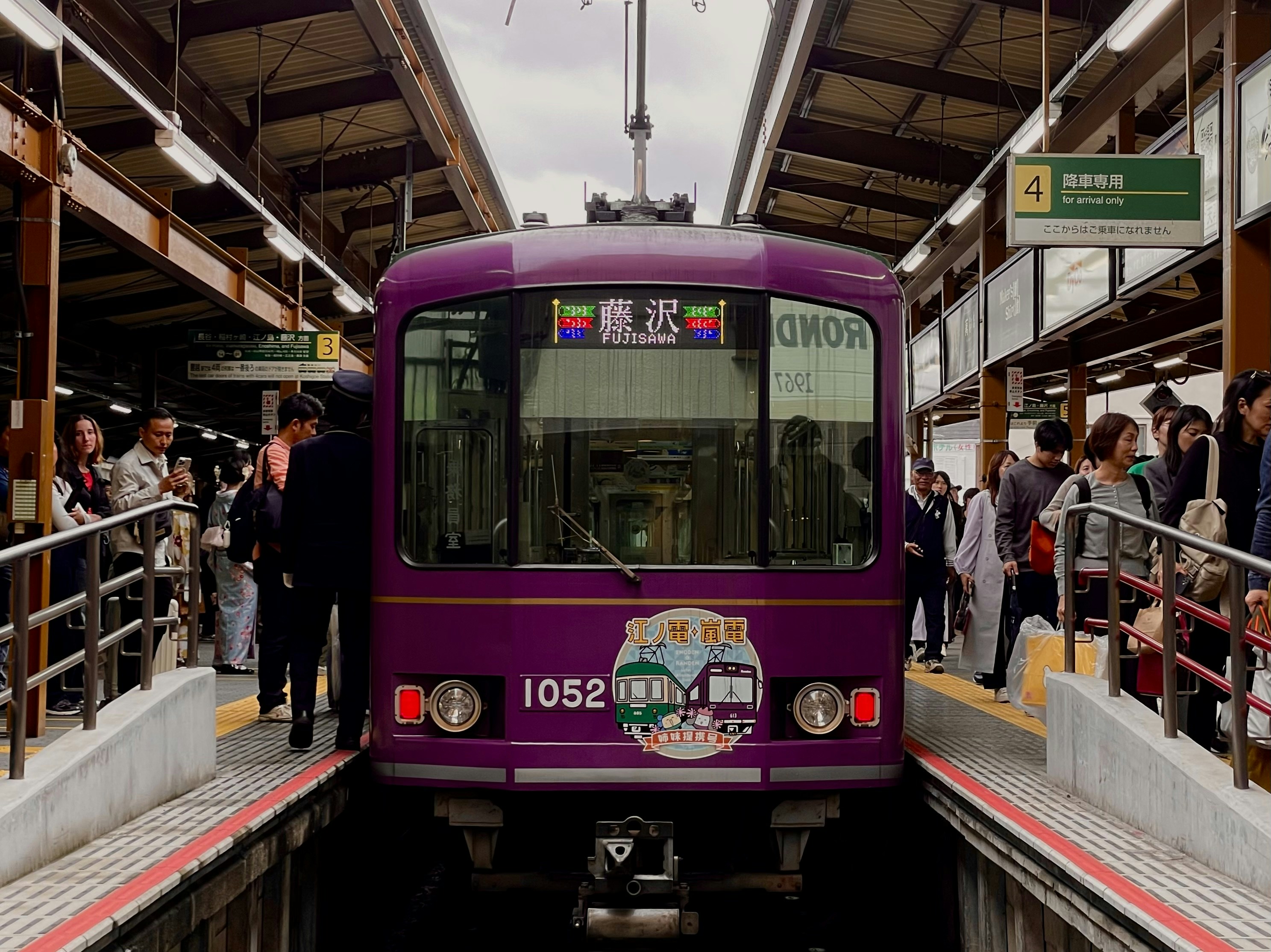 Lavender Tram at a Bustling Urban Platform, Framed by Crowds and Signage
