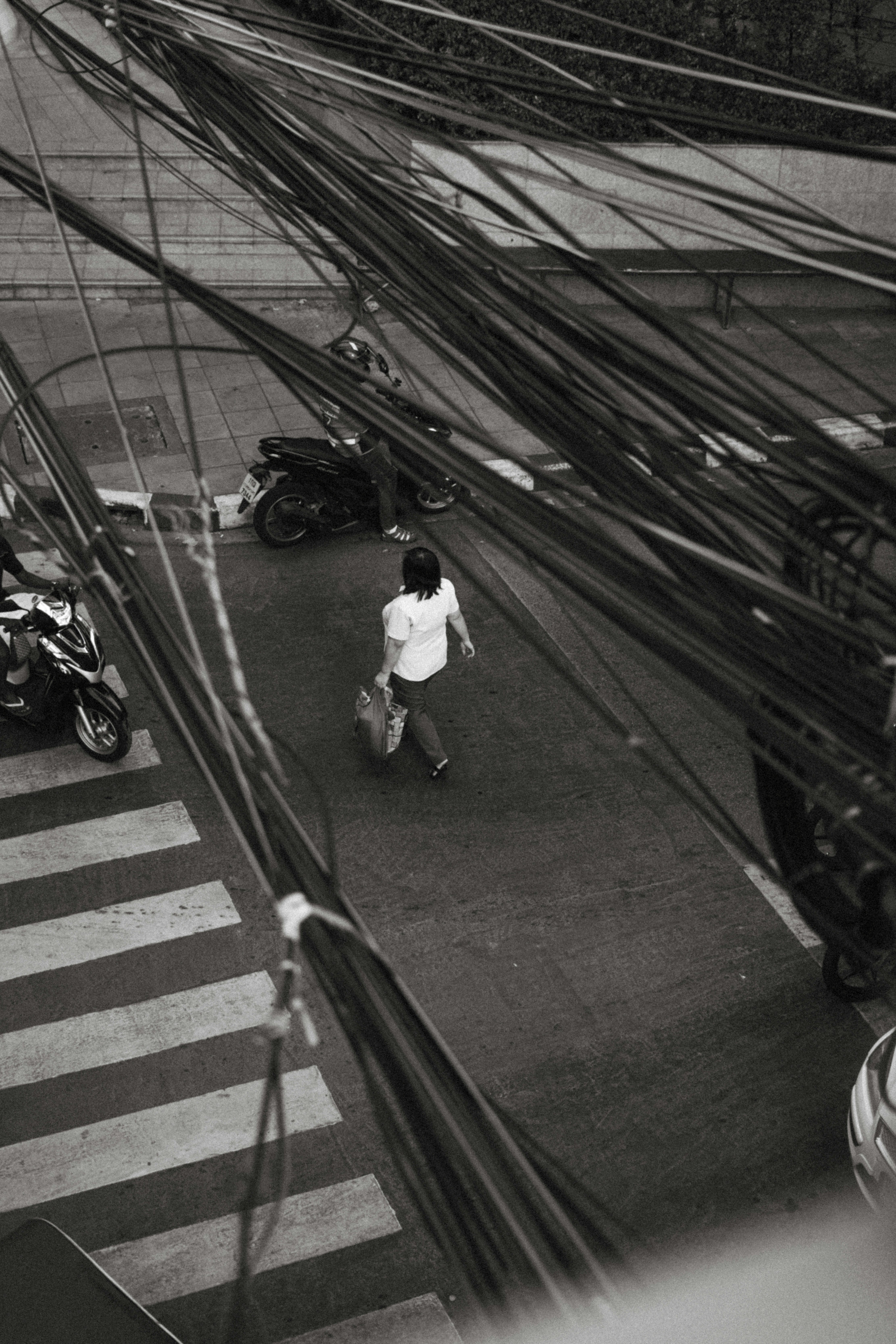 A person walks on a street amidst tangled wires.