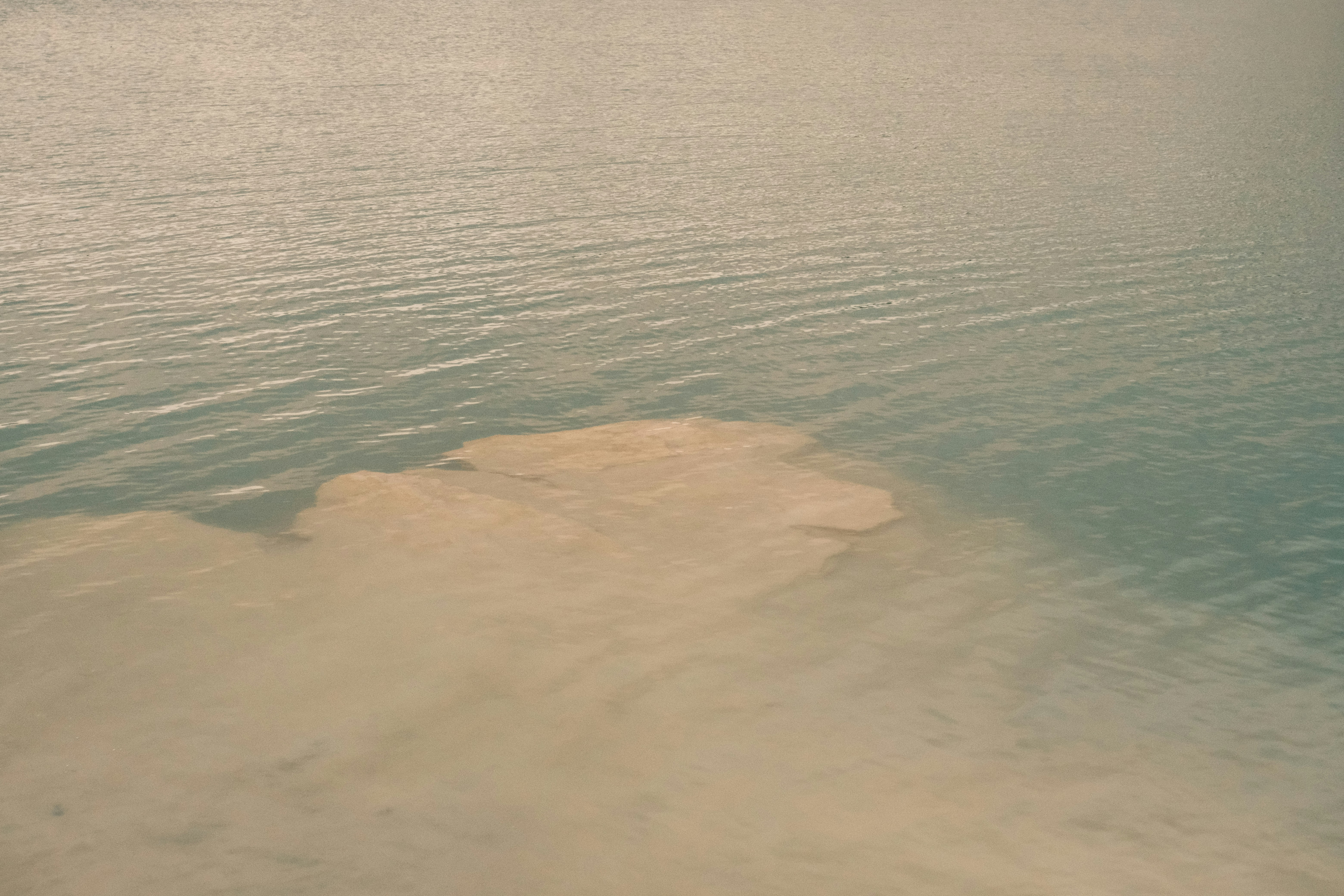 Sand and sediment in turquoise water.