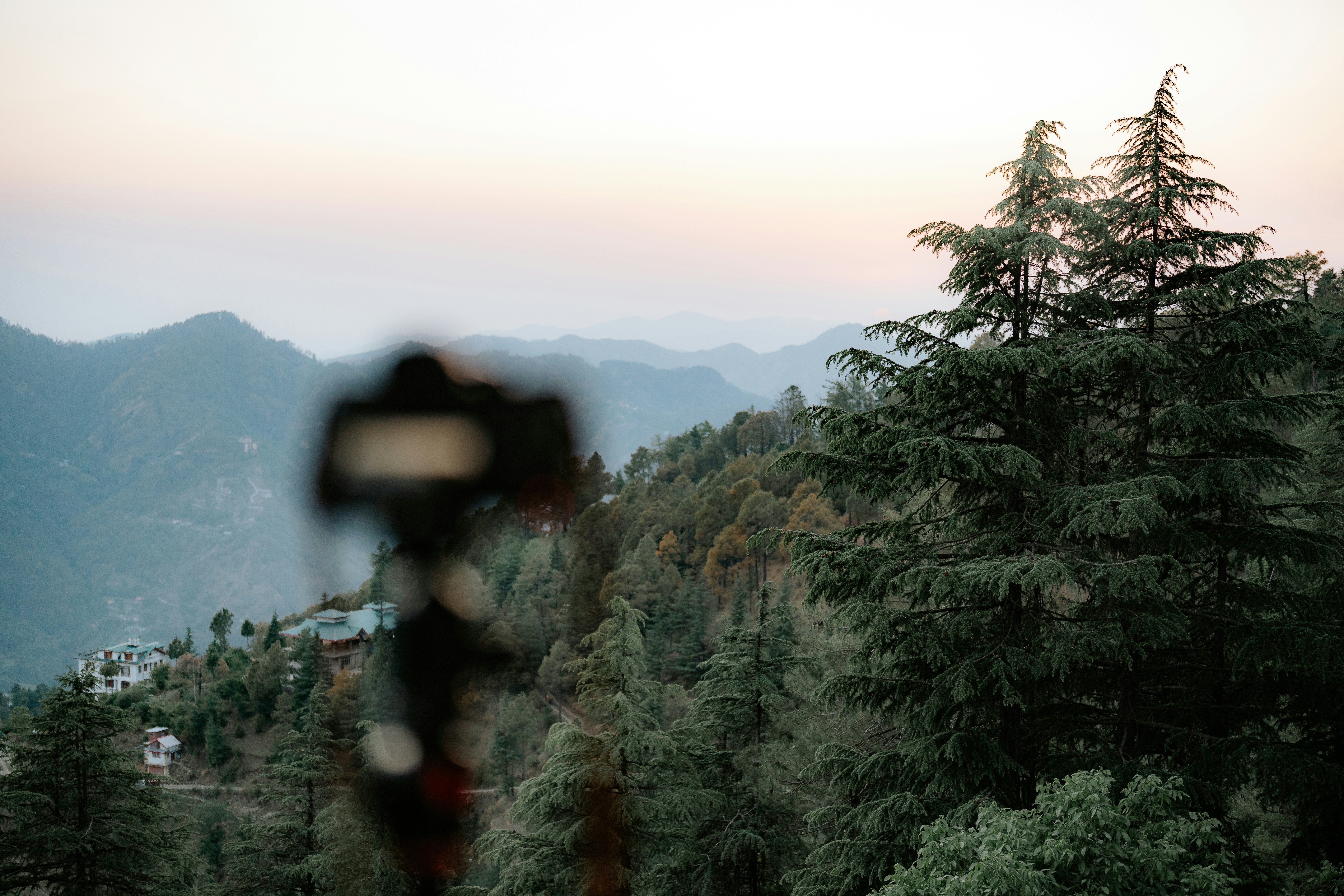 A blurred camera stands in focus against a backdrop of lush mountains and fading light, capturing the essence of exploration and adventure.