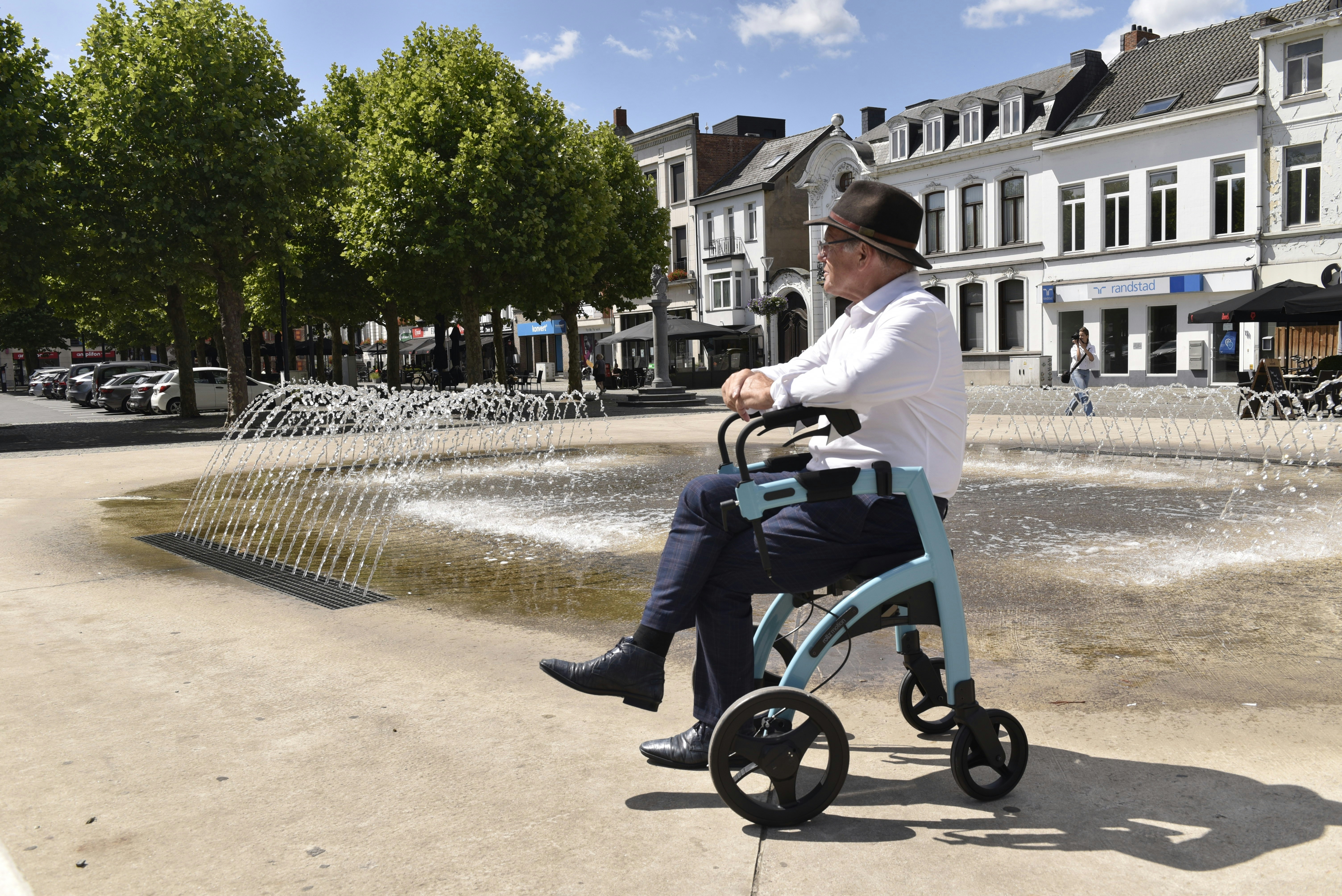 Man sits near a fountain with a mobility aid.