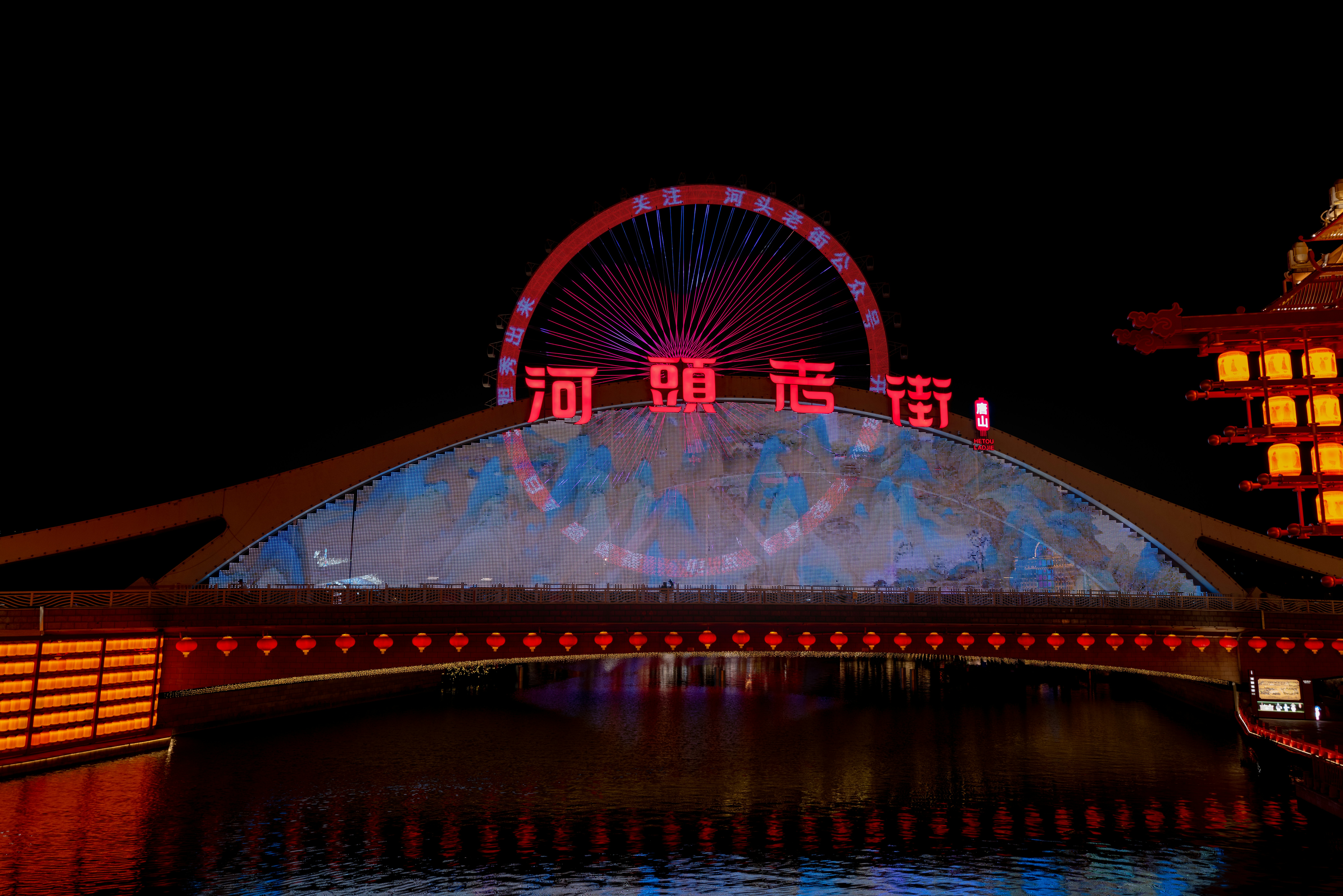 Nighttime bridge with illuminated decorations and chinese characters.