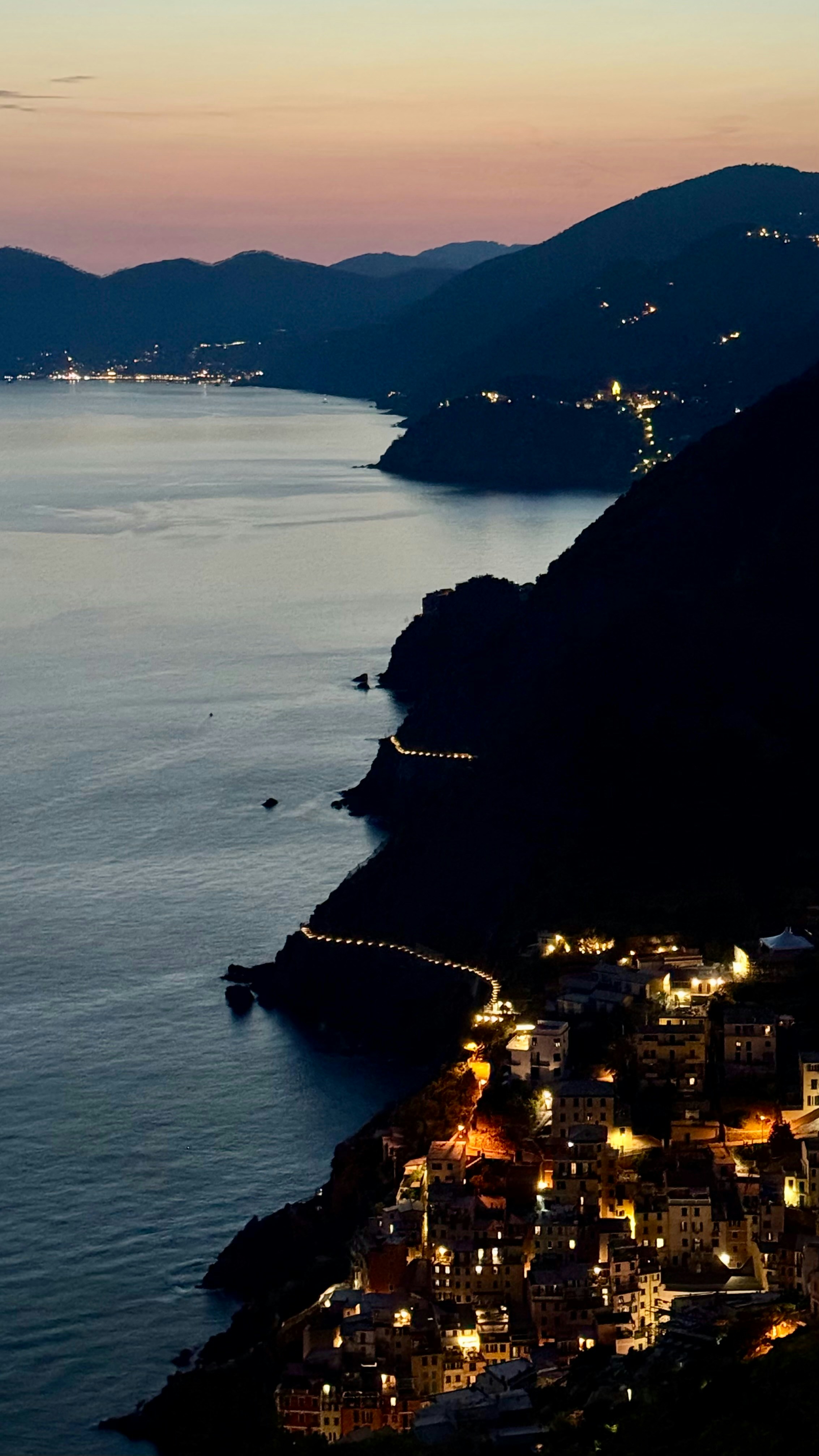 Night view of coastal town with illuminated buildings.