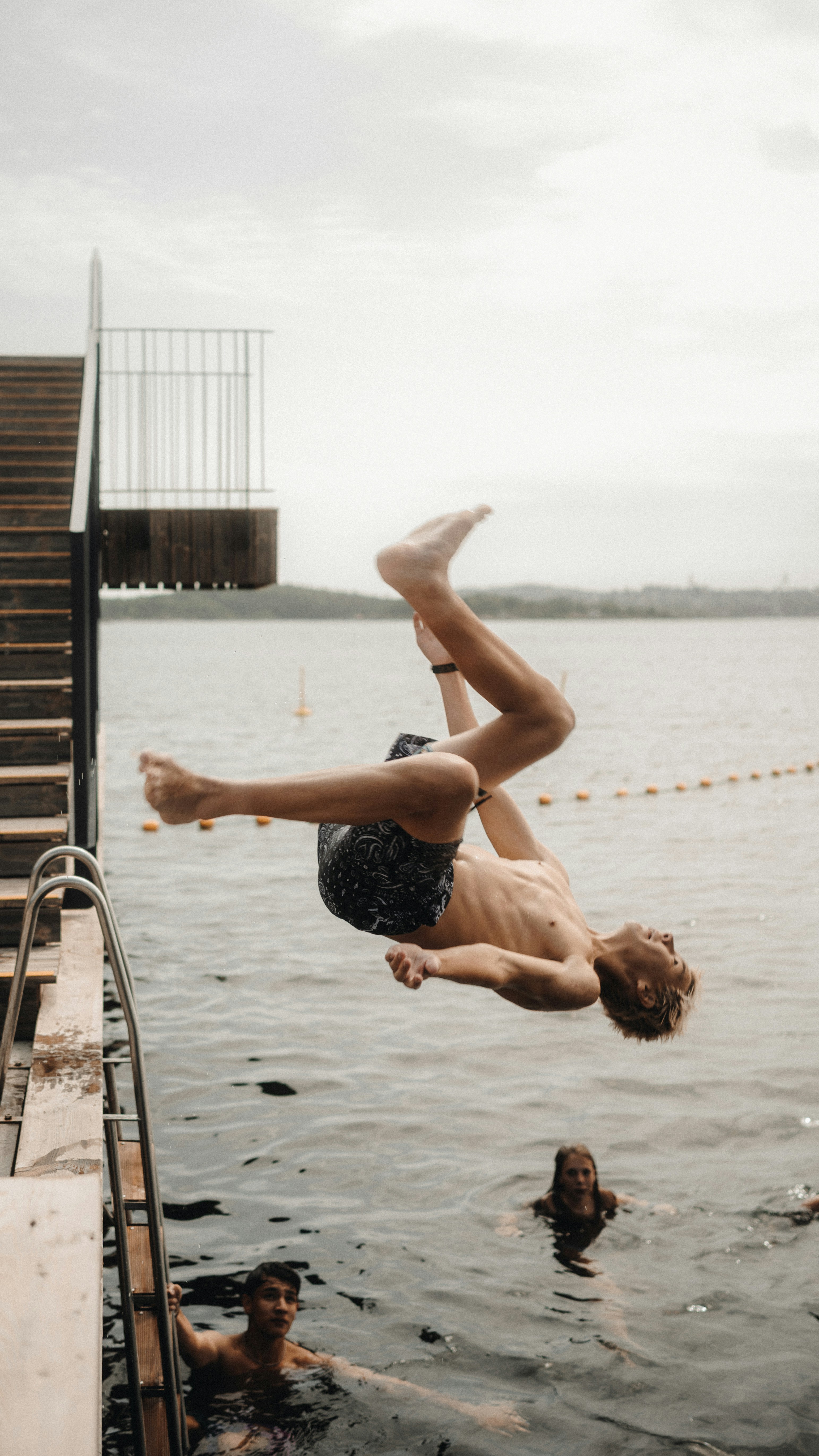 Kid backflips into water | A man performs a backflip into the water.