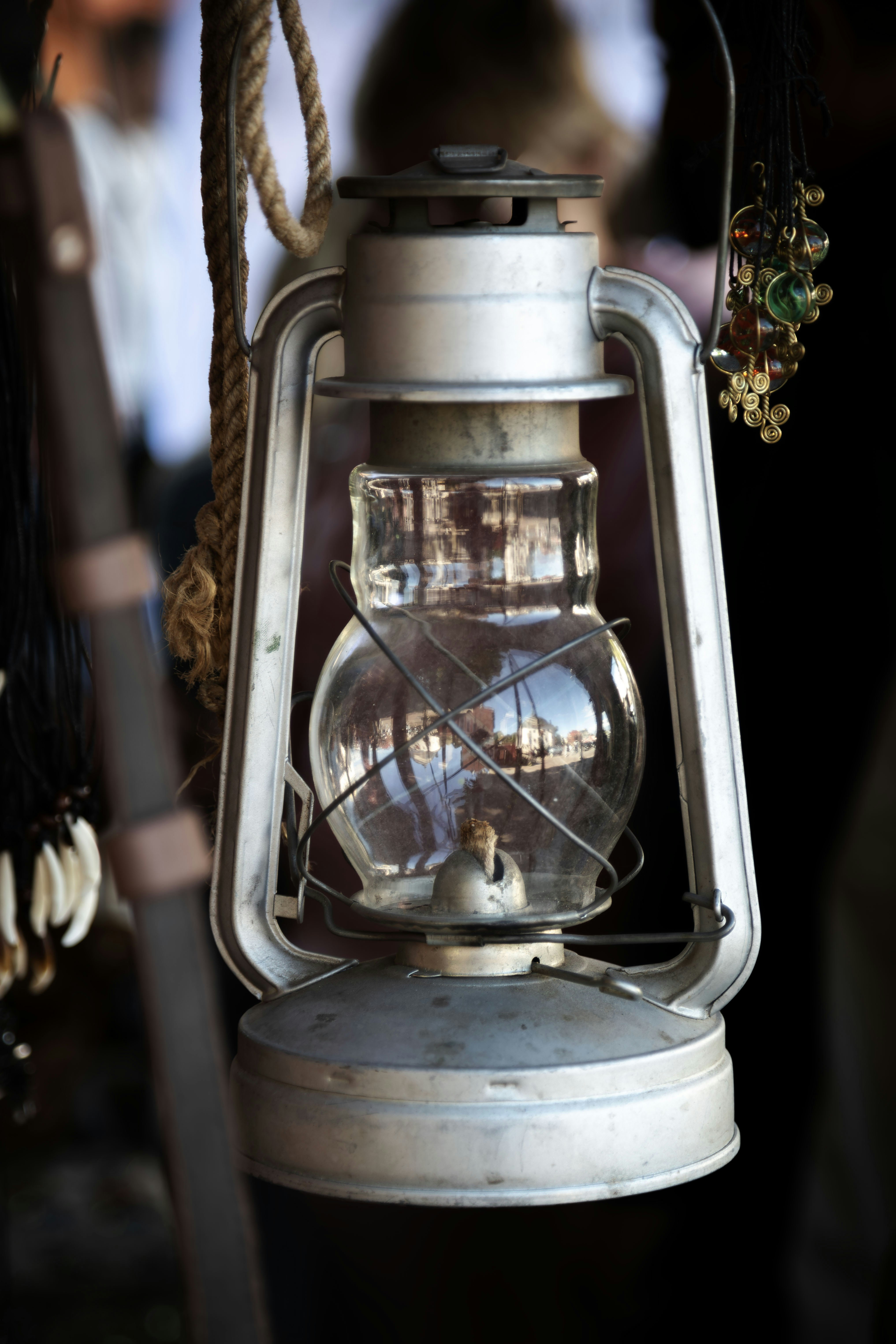 Vintage oil lantern hanging amidst a bustling market, reflecting the surrounding activity and ambiance.