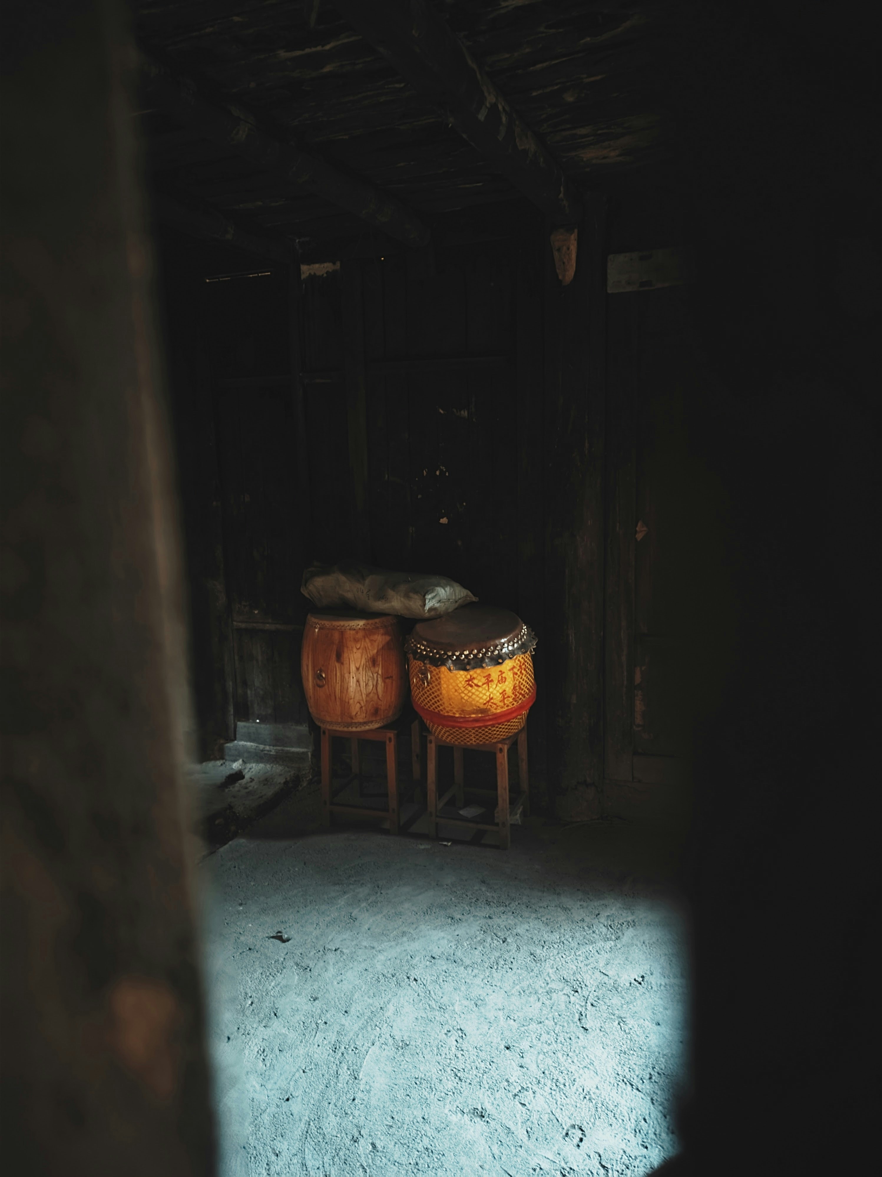 Two wooden drums sit in a dimly lit room.