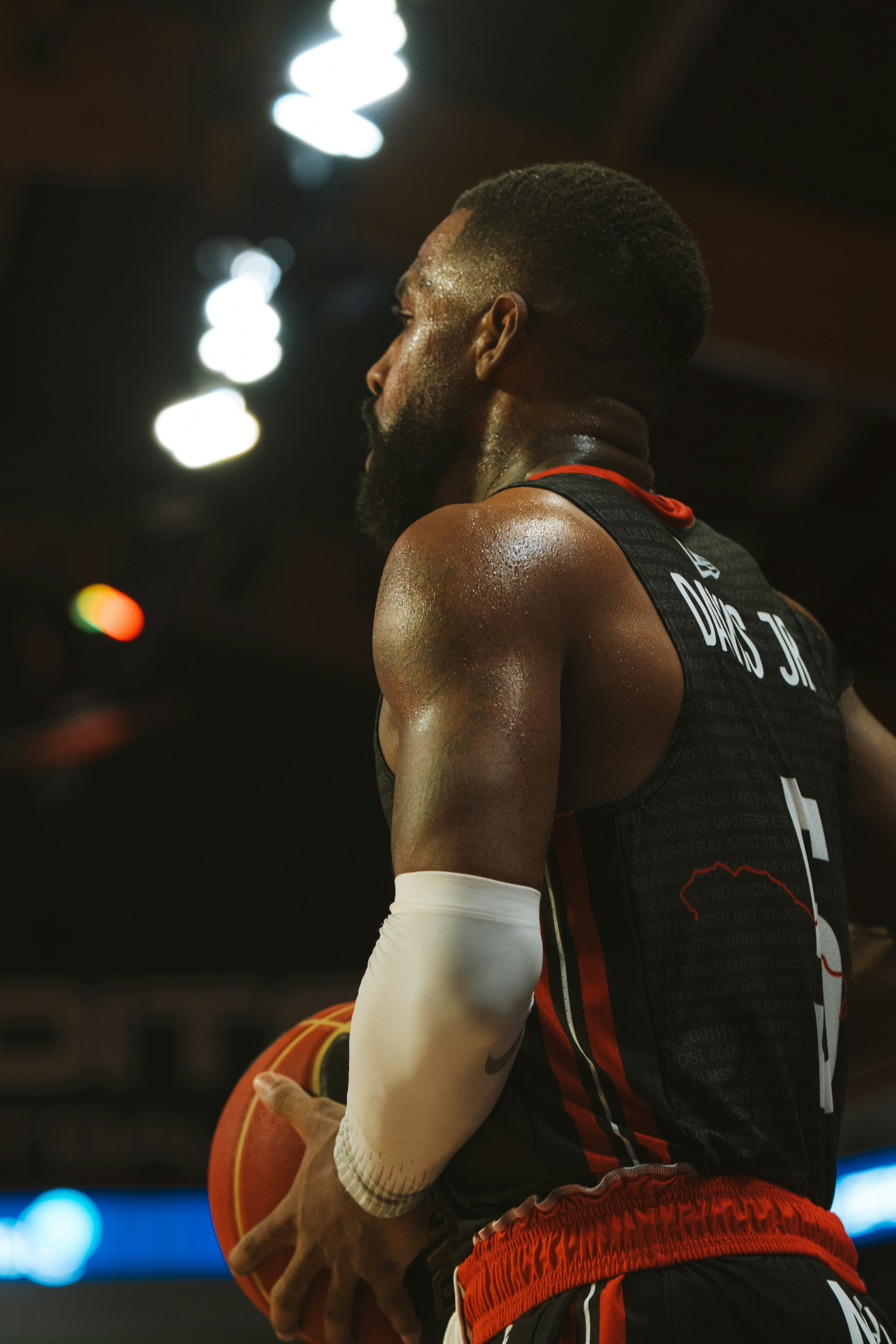 Athlete preparing to make a move on the basketball court, showcasing focus and intensity under the arena lights.