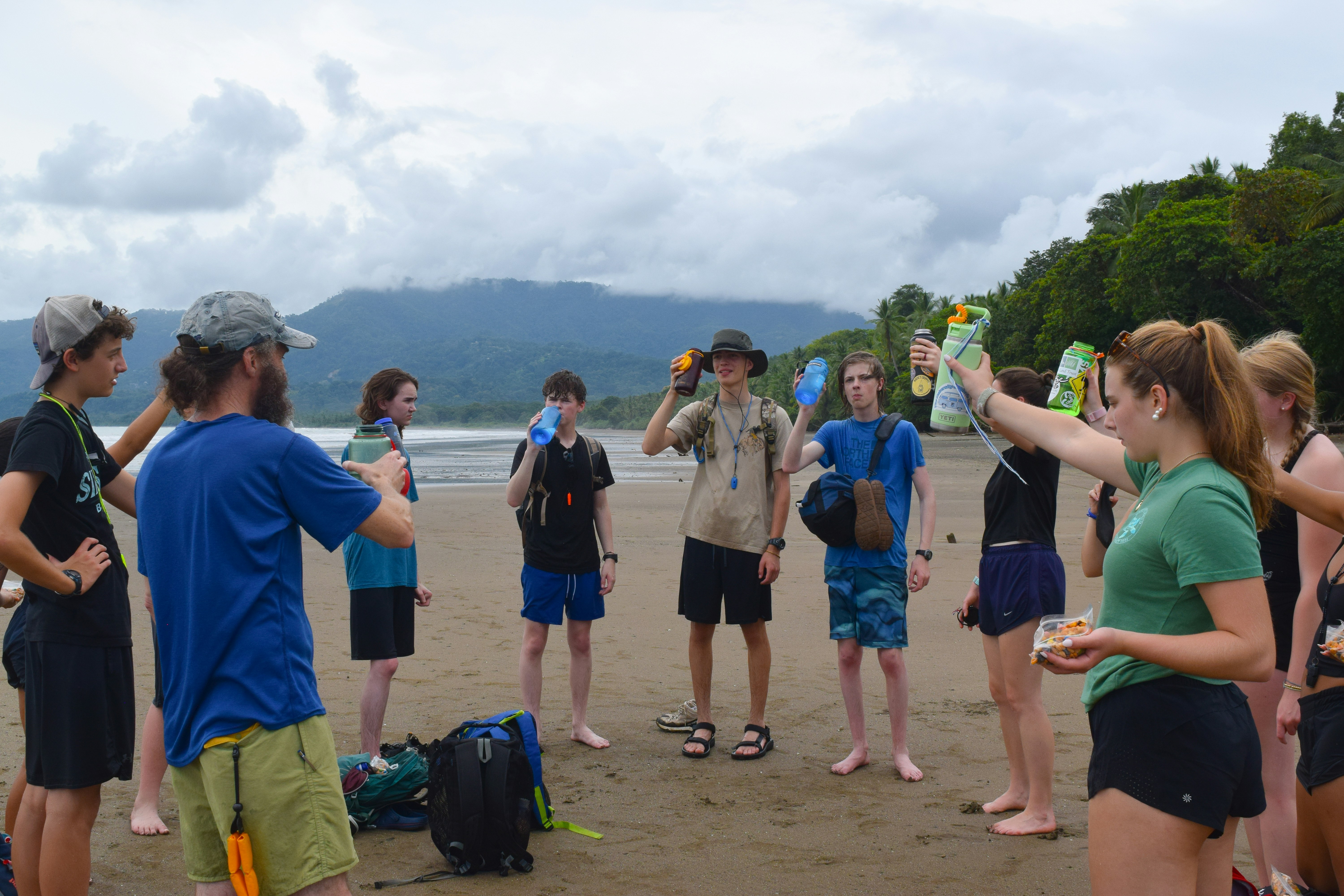 Beached Circle: A Coastal Camp Group Toasts on Wind-Swept Sand