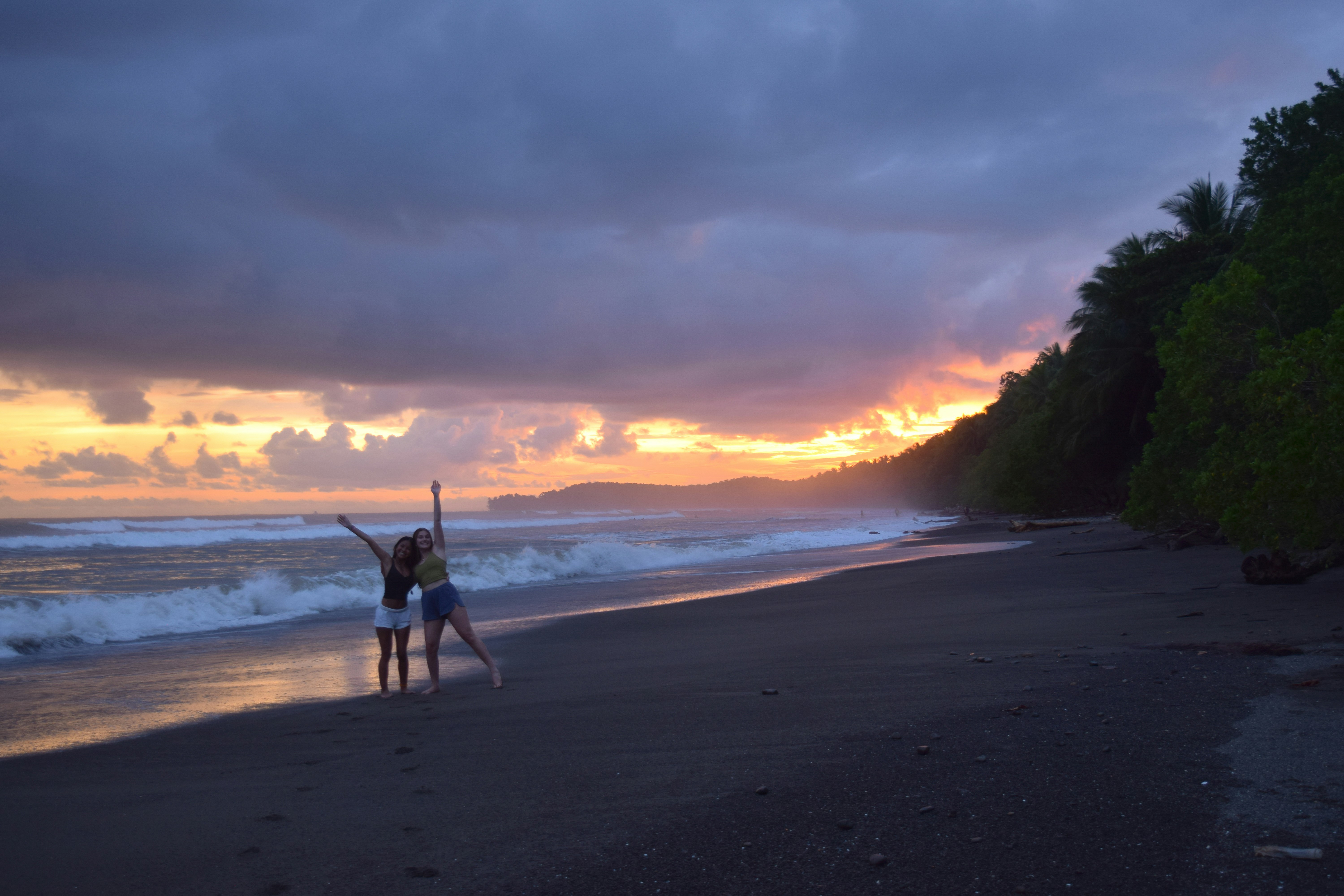 Two friends enjoy a stunning sunset at the beach.