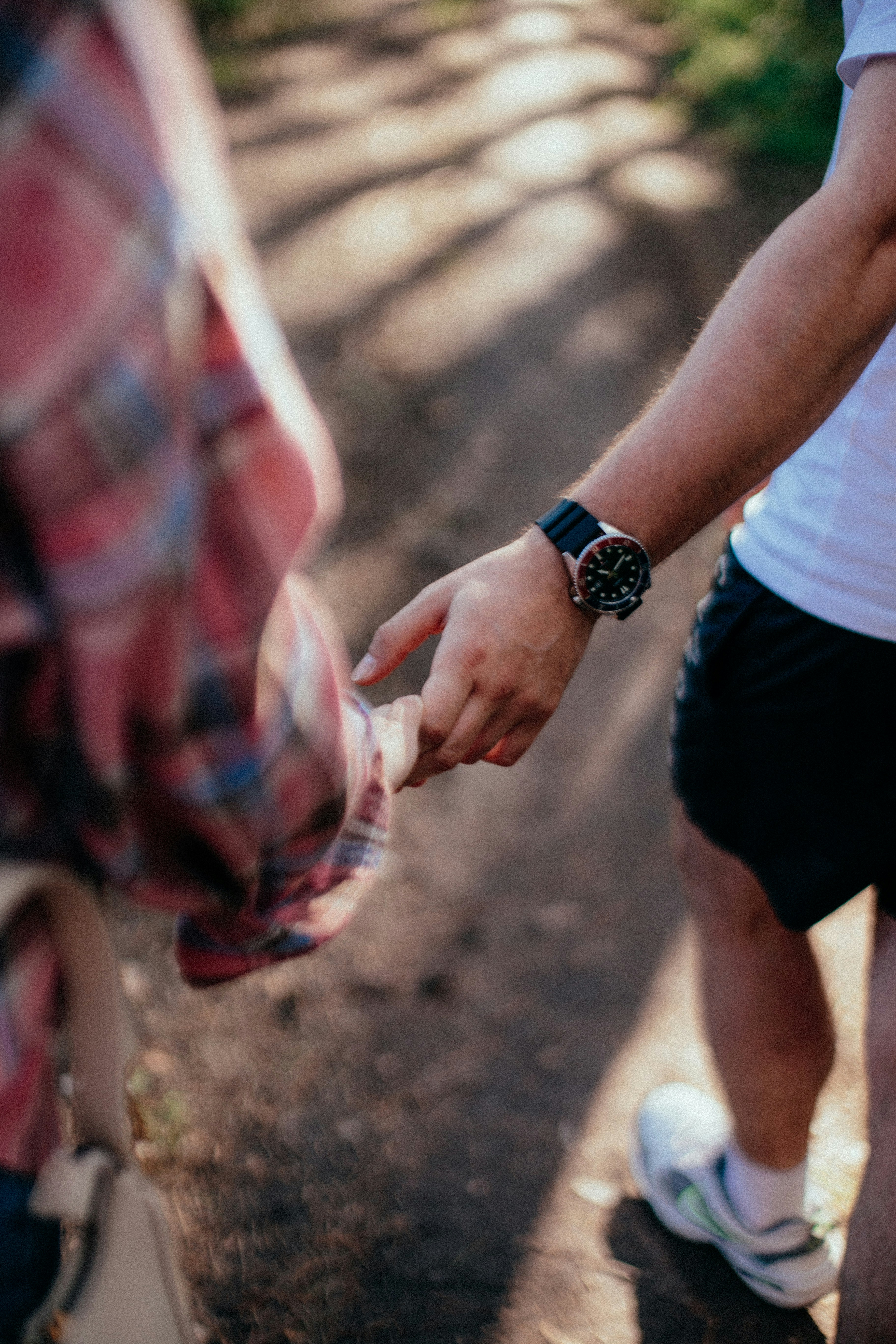 A couple holds hands while walking outdoors.