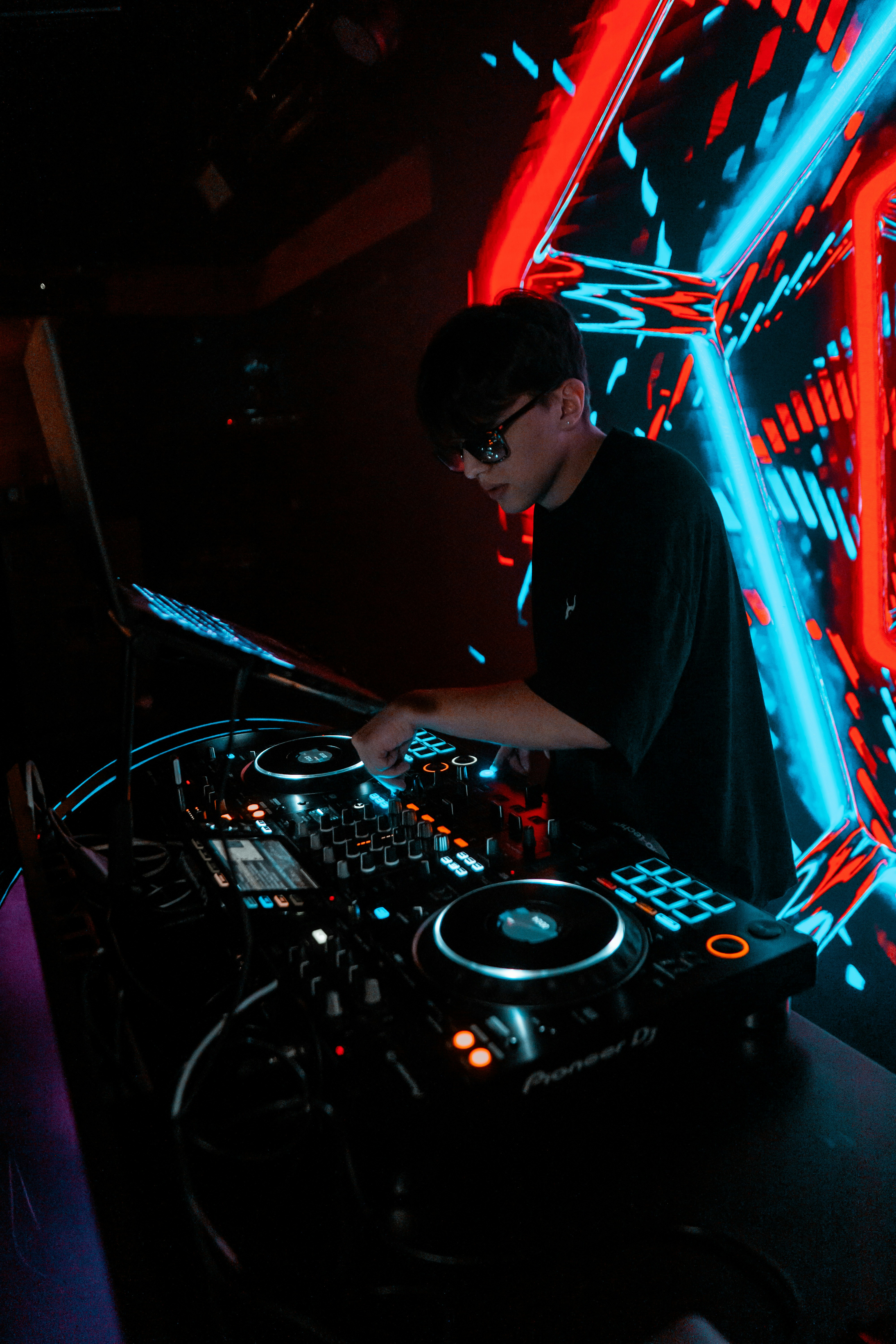 DJ portrait in club | A dj plays music in a dimly lit, colorful club.