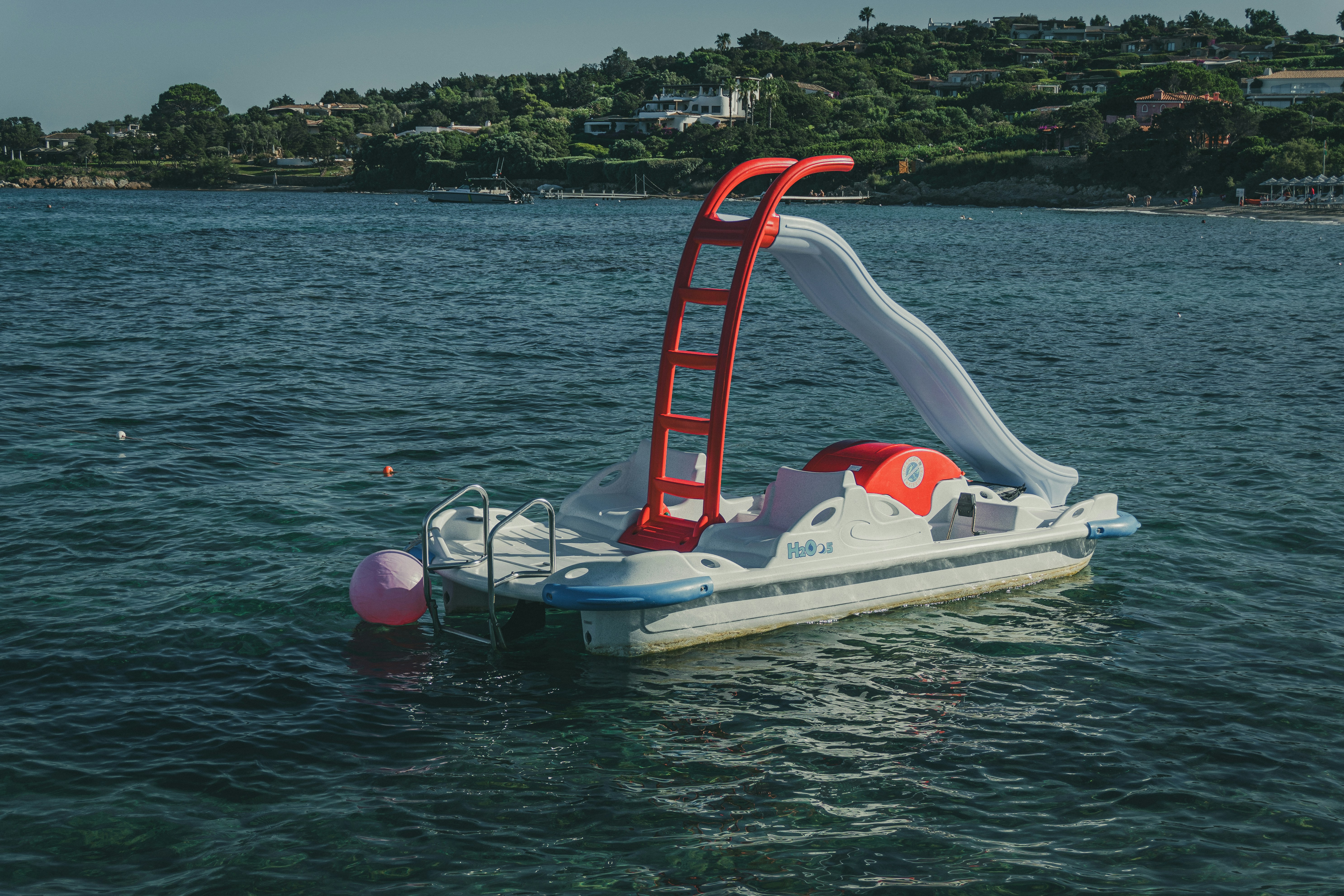 A paddle boat with a slide floats on water.