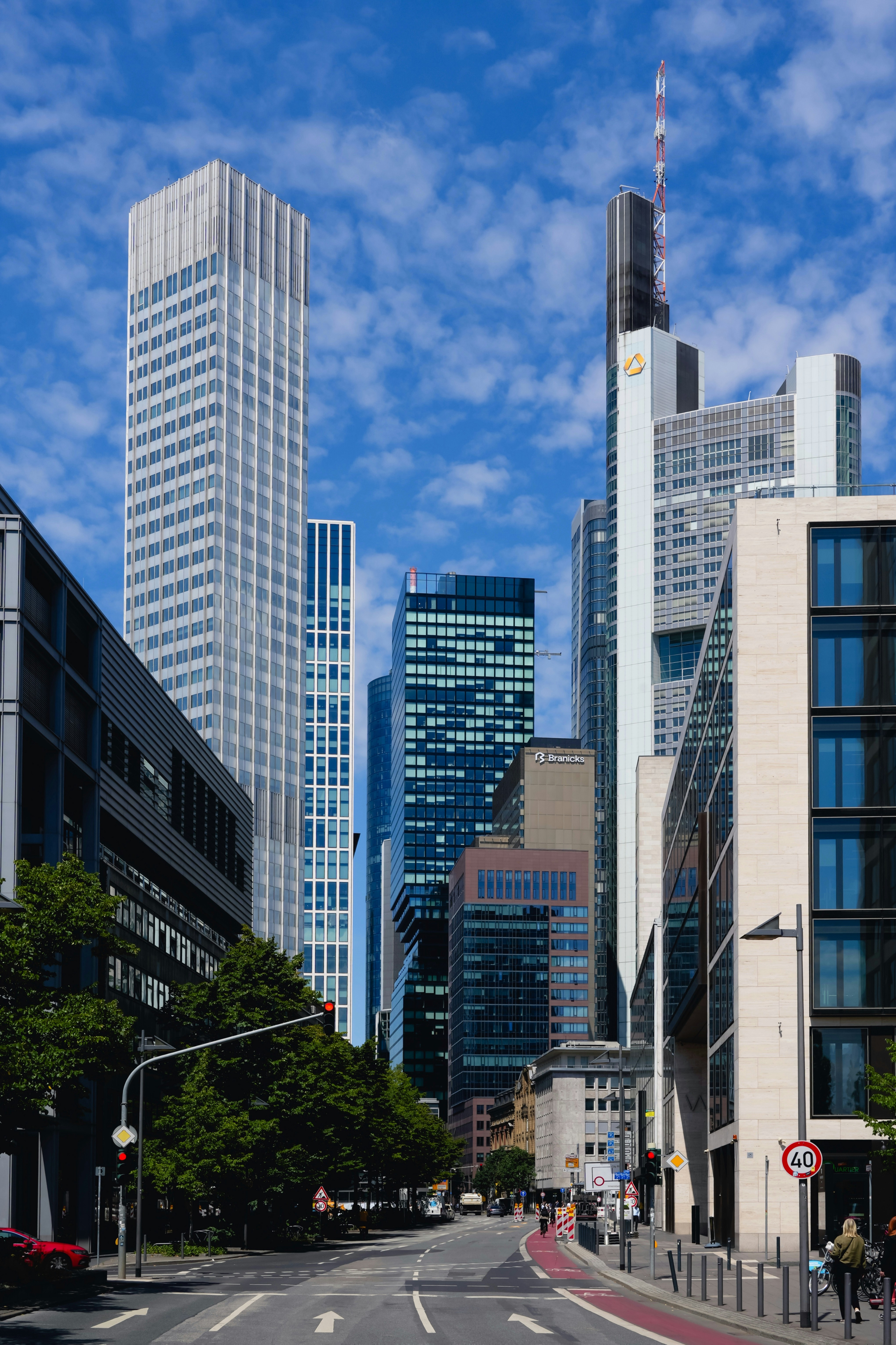 A vibrant cityscape showcasing a cluster of modern skyscrapers against a backdrop of a blue sky with scattered clouds.