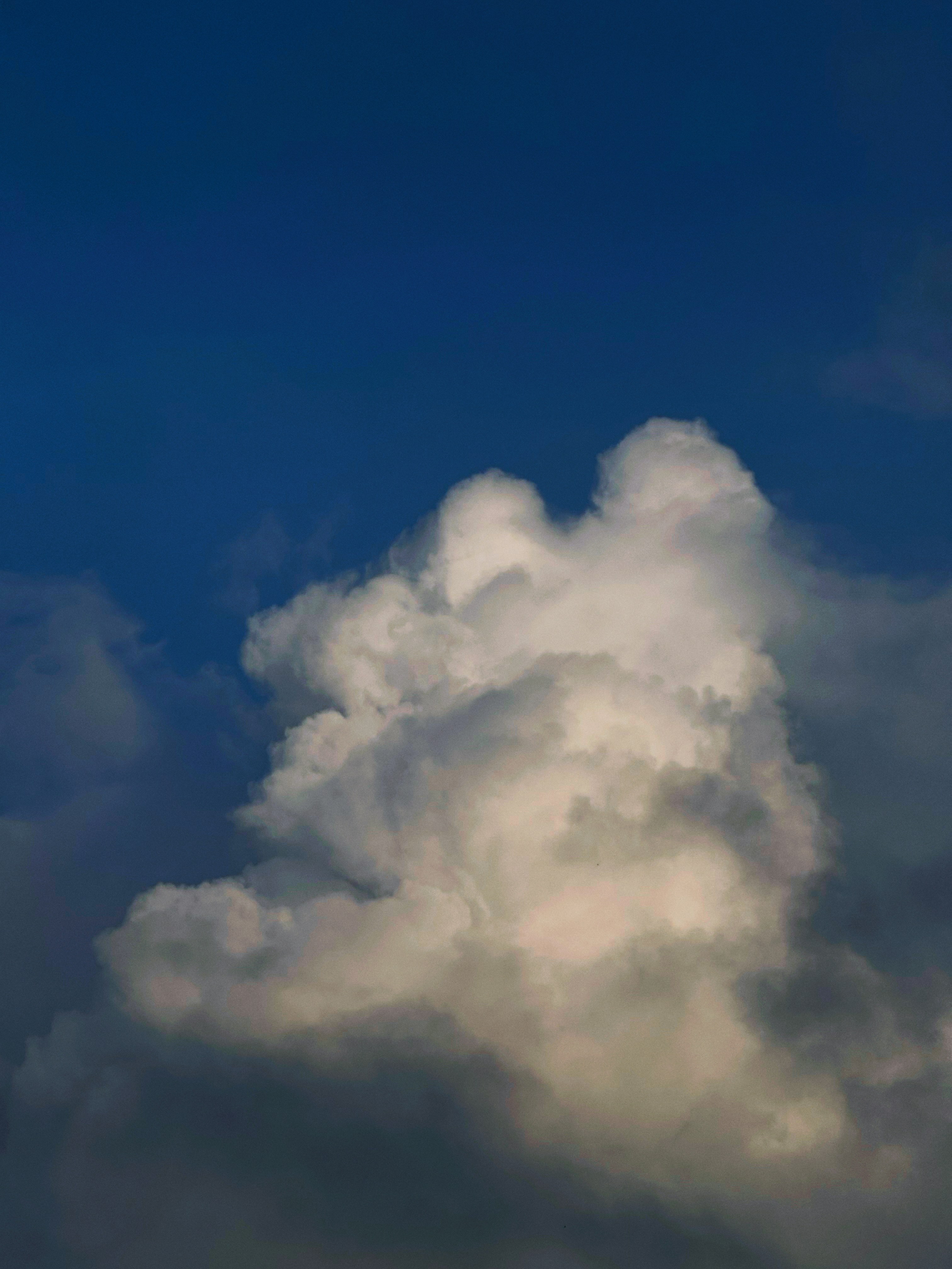 Fluffy white clouds drifting against a deep blue backdrop, capturing the serene beauty of a clear day.