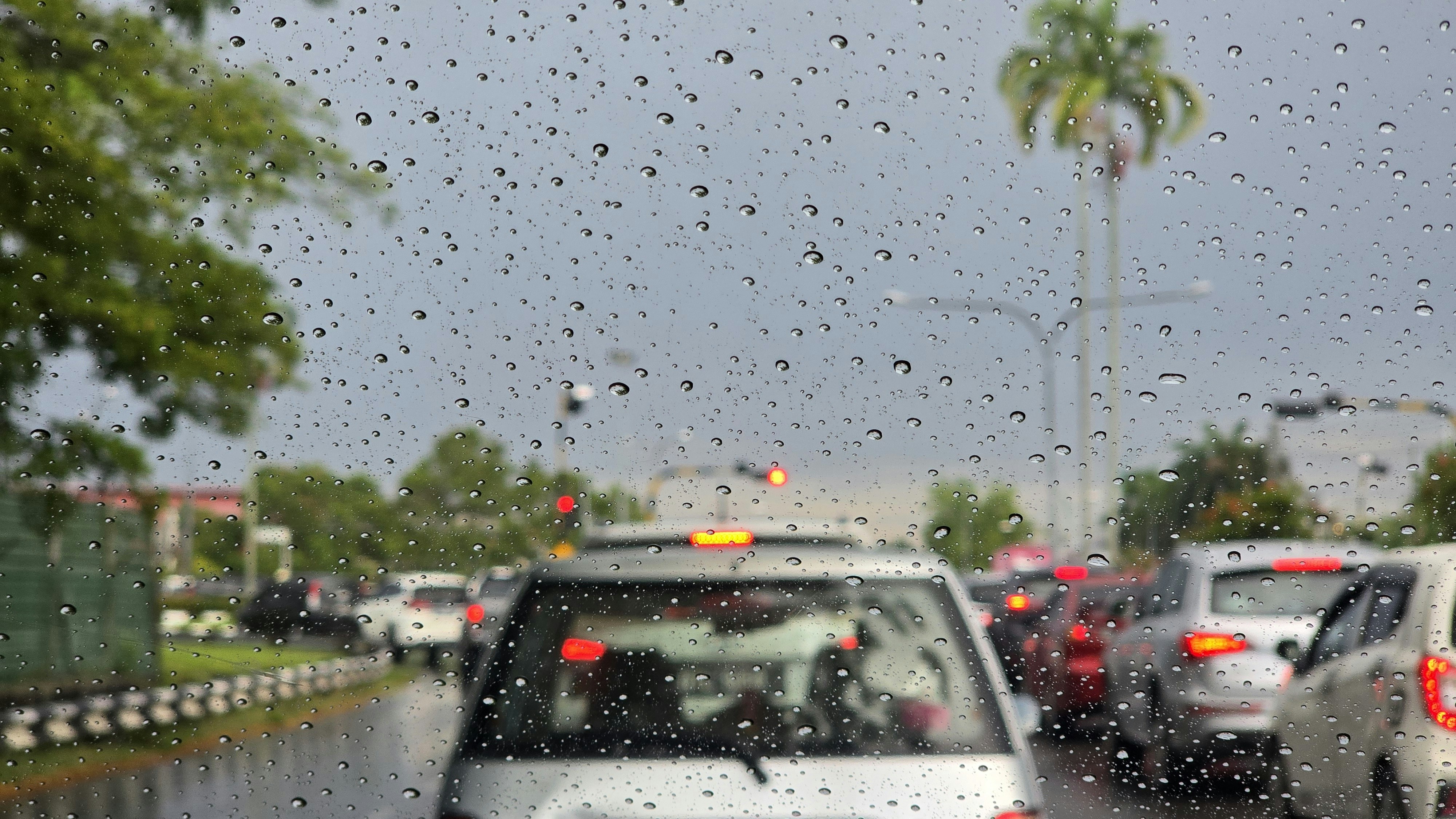 A water droplet on the windshield | Raindrops blur a busy street and traffic.