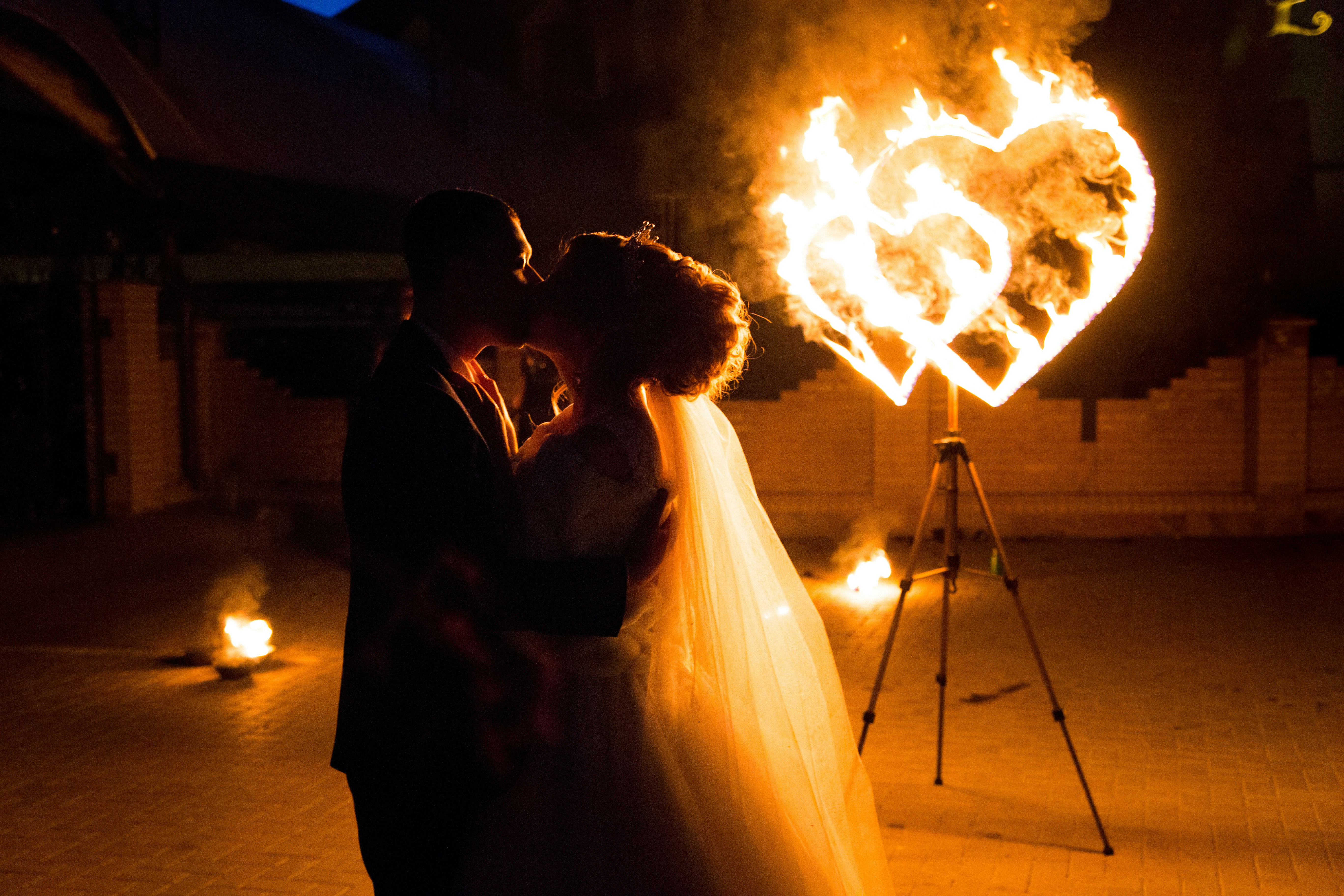 Embrace Beneath a Flaming Heart: Night Wedding Portrait