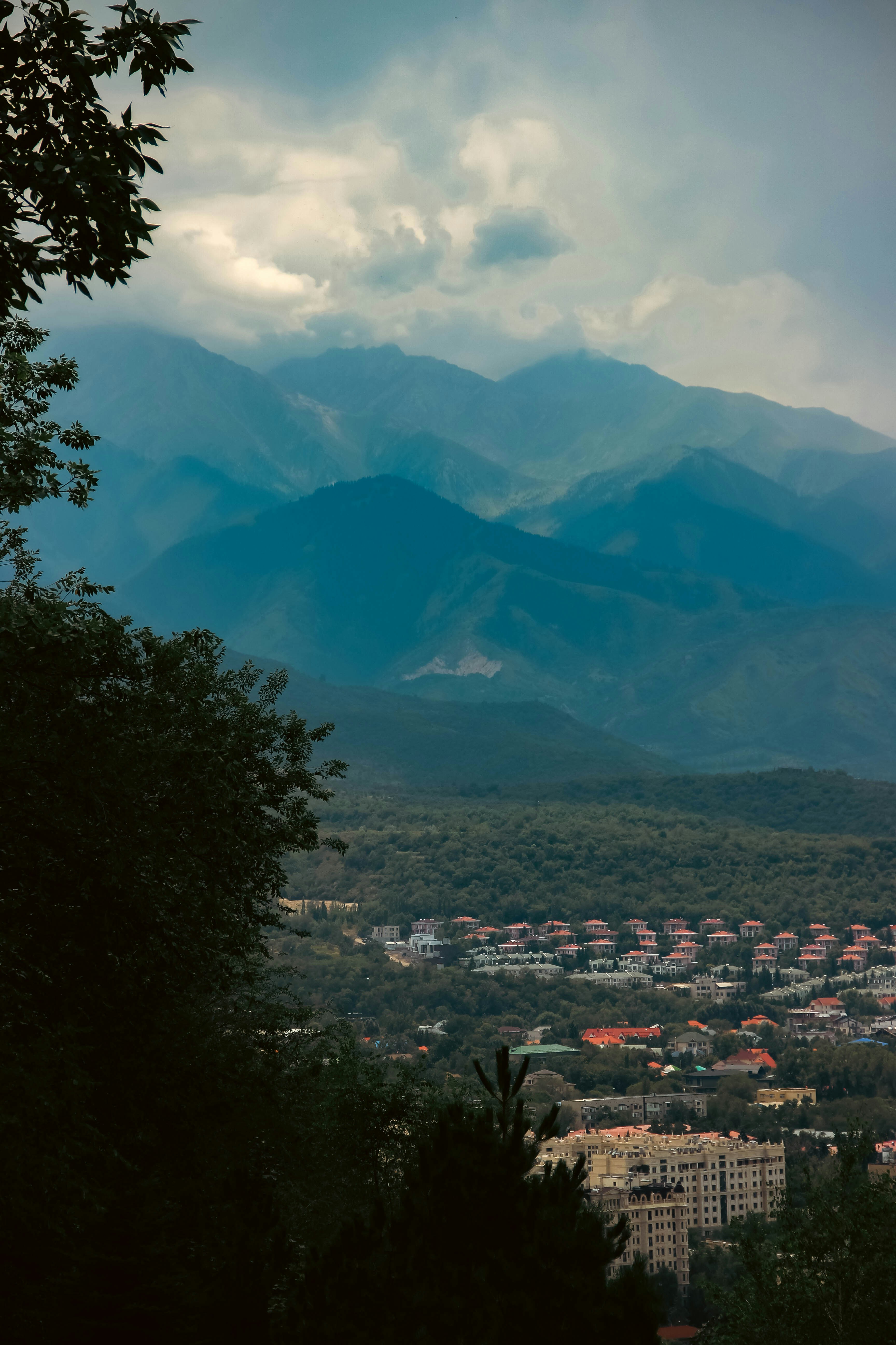Mountains loom over a town under a cloudy sky.