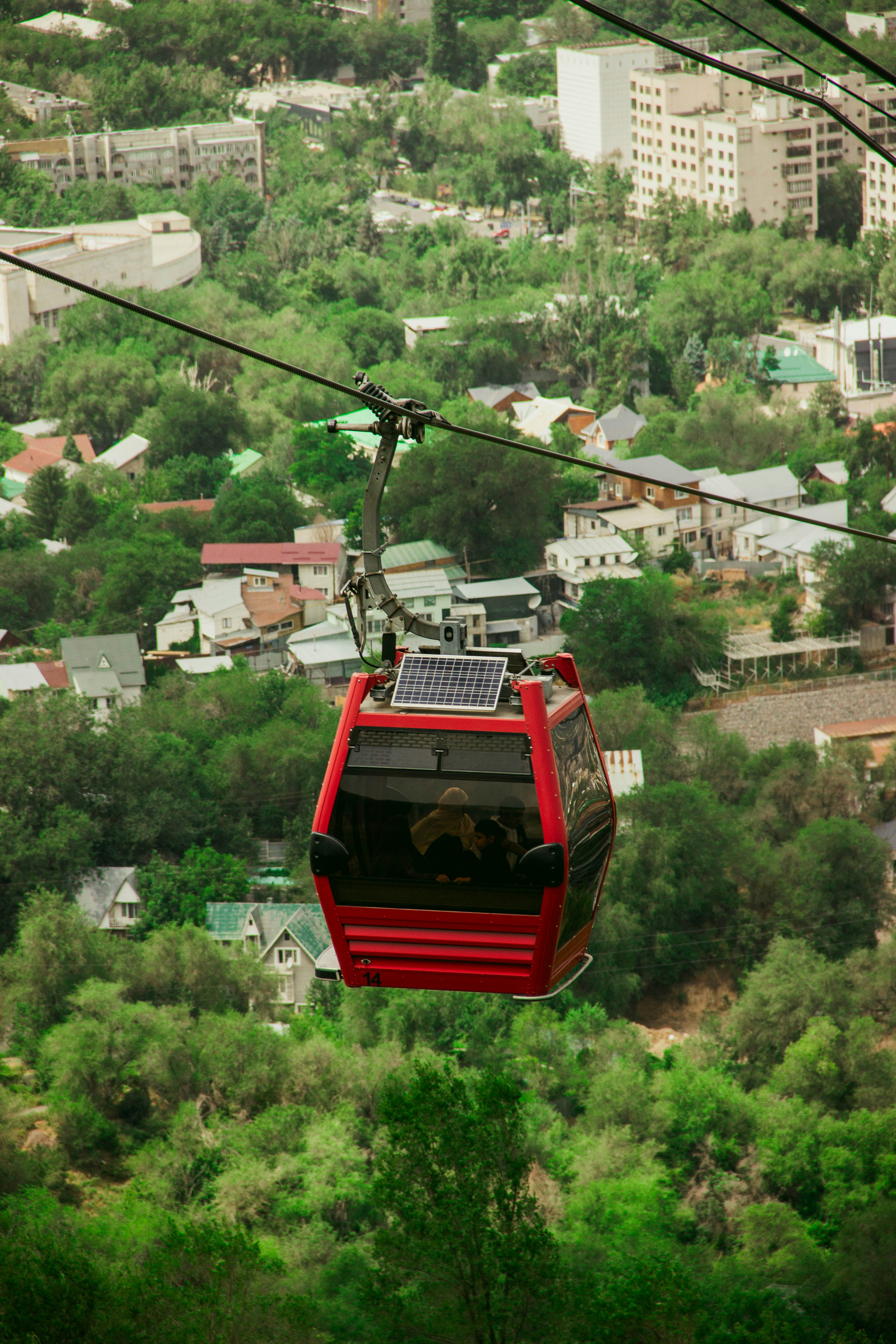 A red gondola travels above houses.