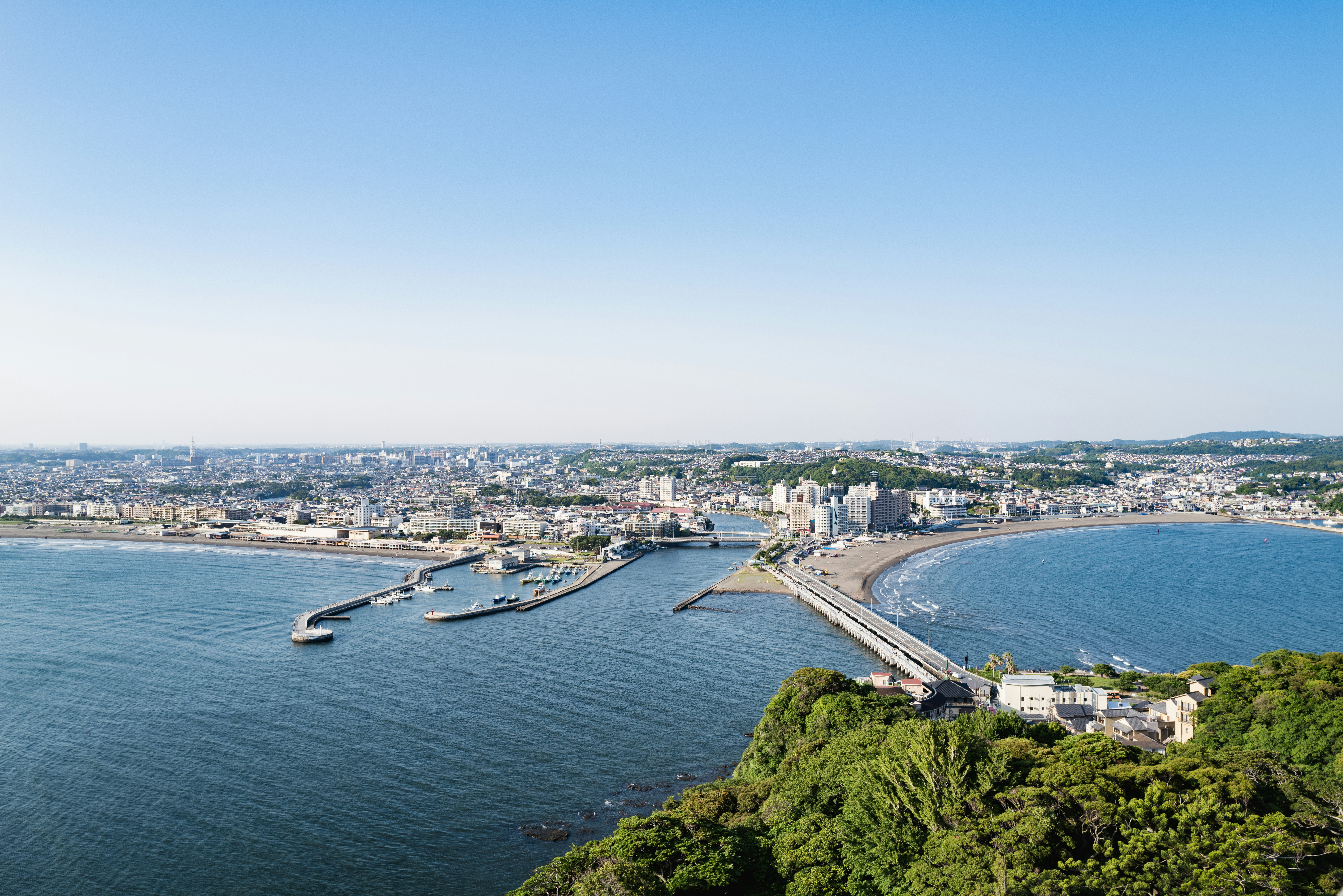 Cliffside Panorama: A Curved Harbor and City Srawl Under a Clear Blue Sky