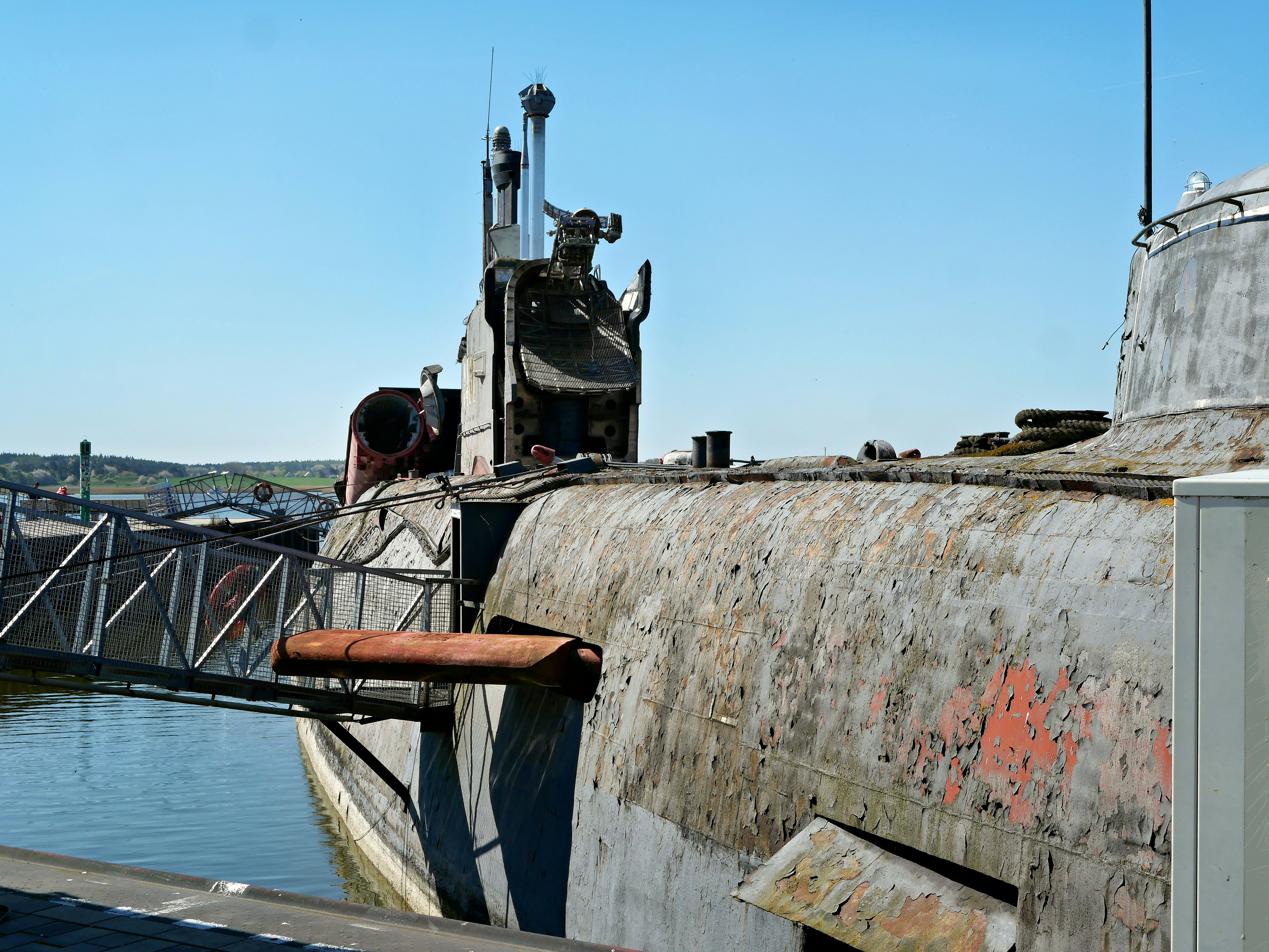 Weathered submarine docked at a waterfront, showcasing its intricate details and historical significance.