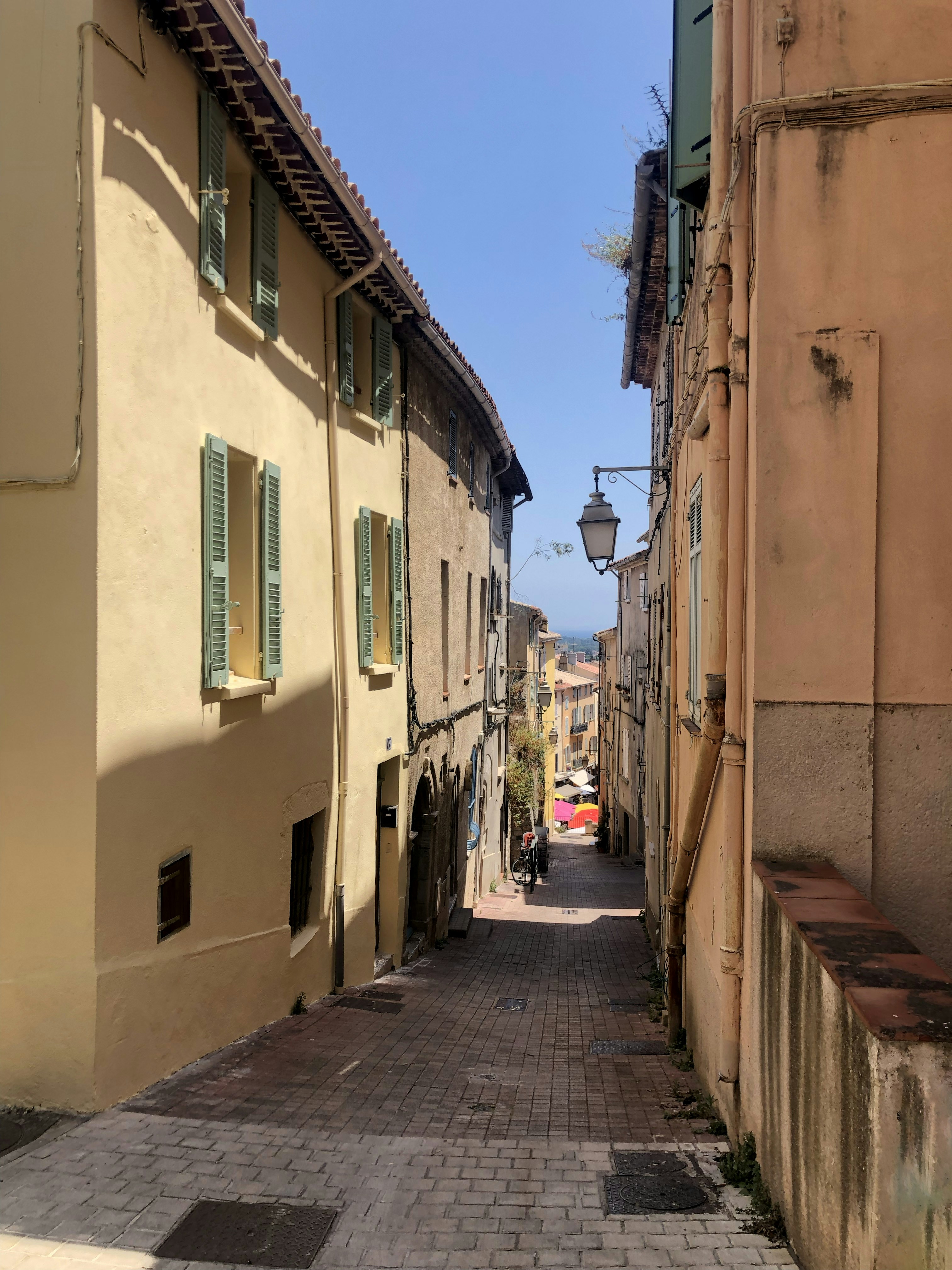 hyeres, france, | Narrow cobblestone street with colorful buildings.