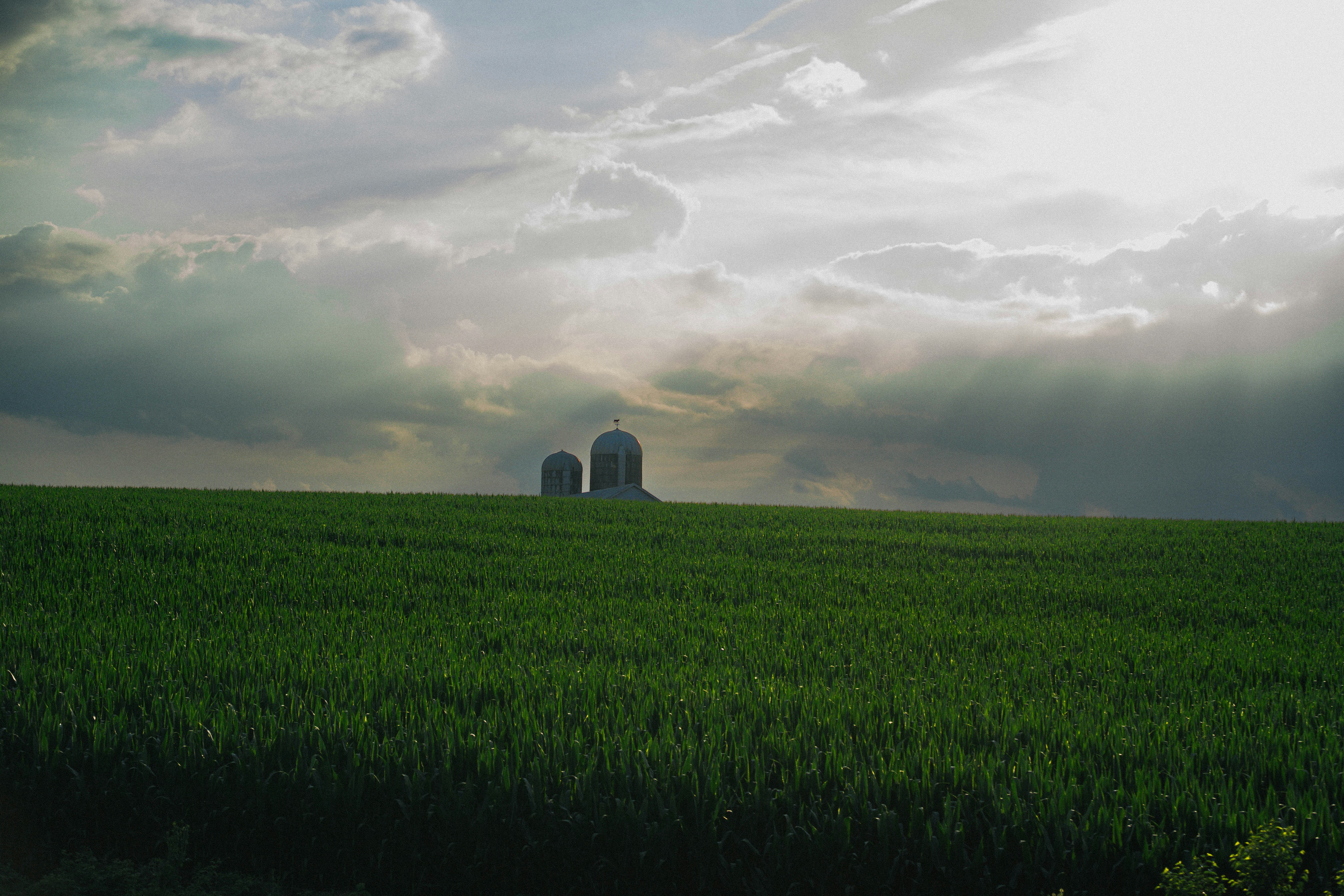 Fields and silos stand under a cloudy sky.