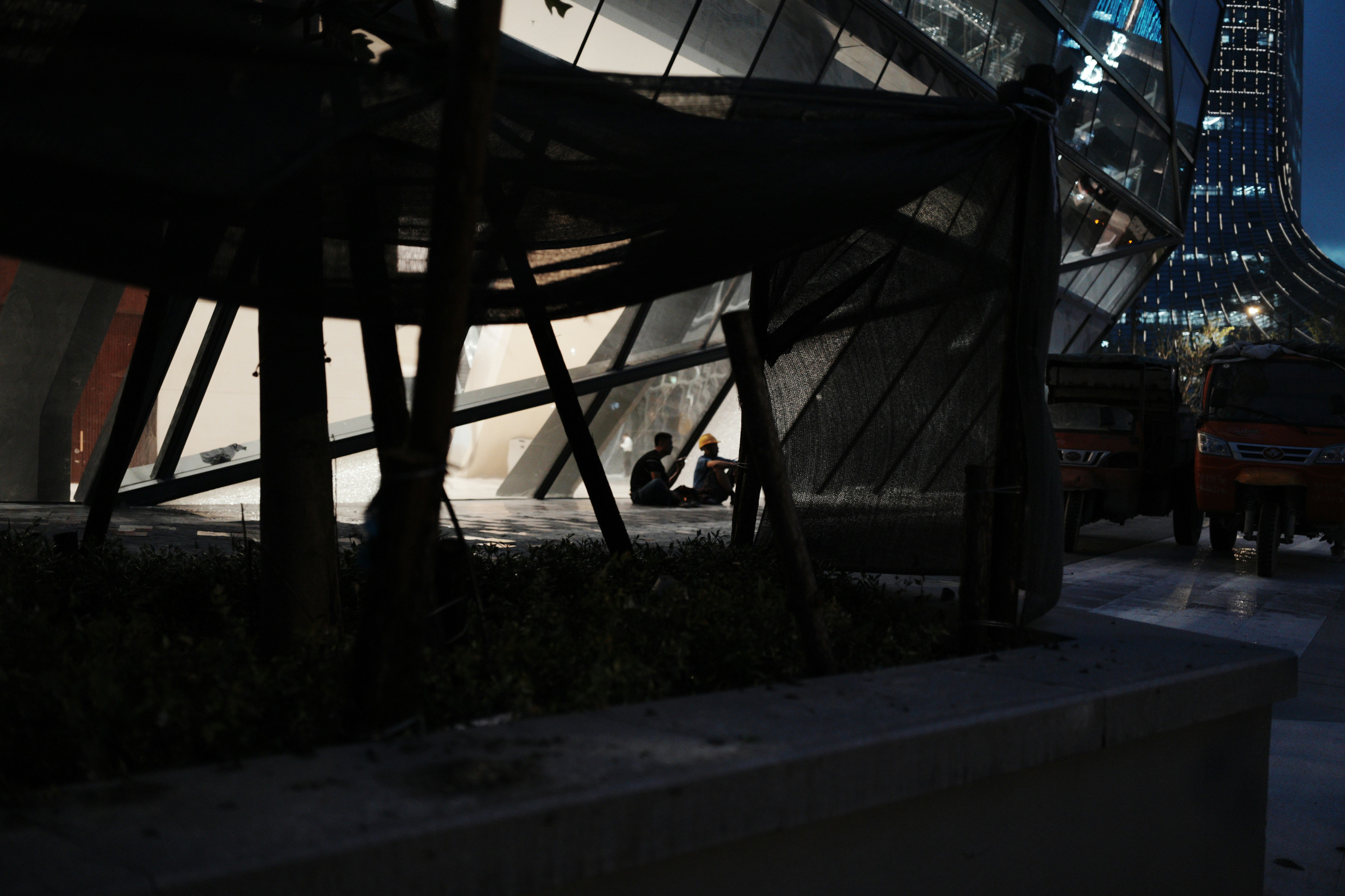 People sit near a modern building at dusk.