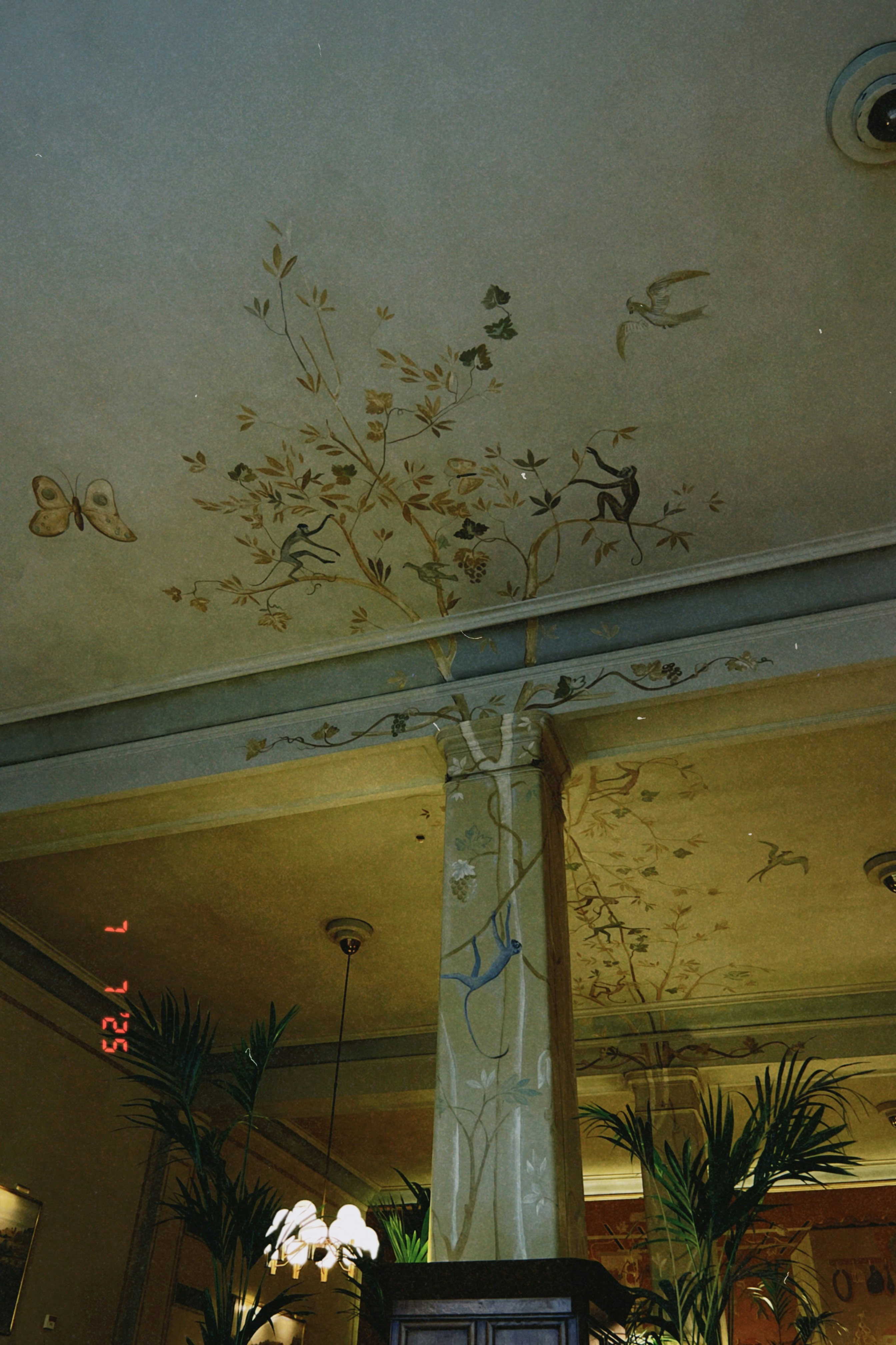 Floral and fauna murals are painted on a ceiling.