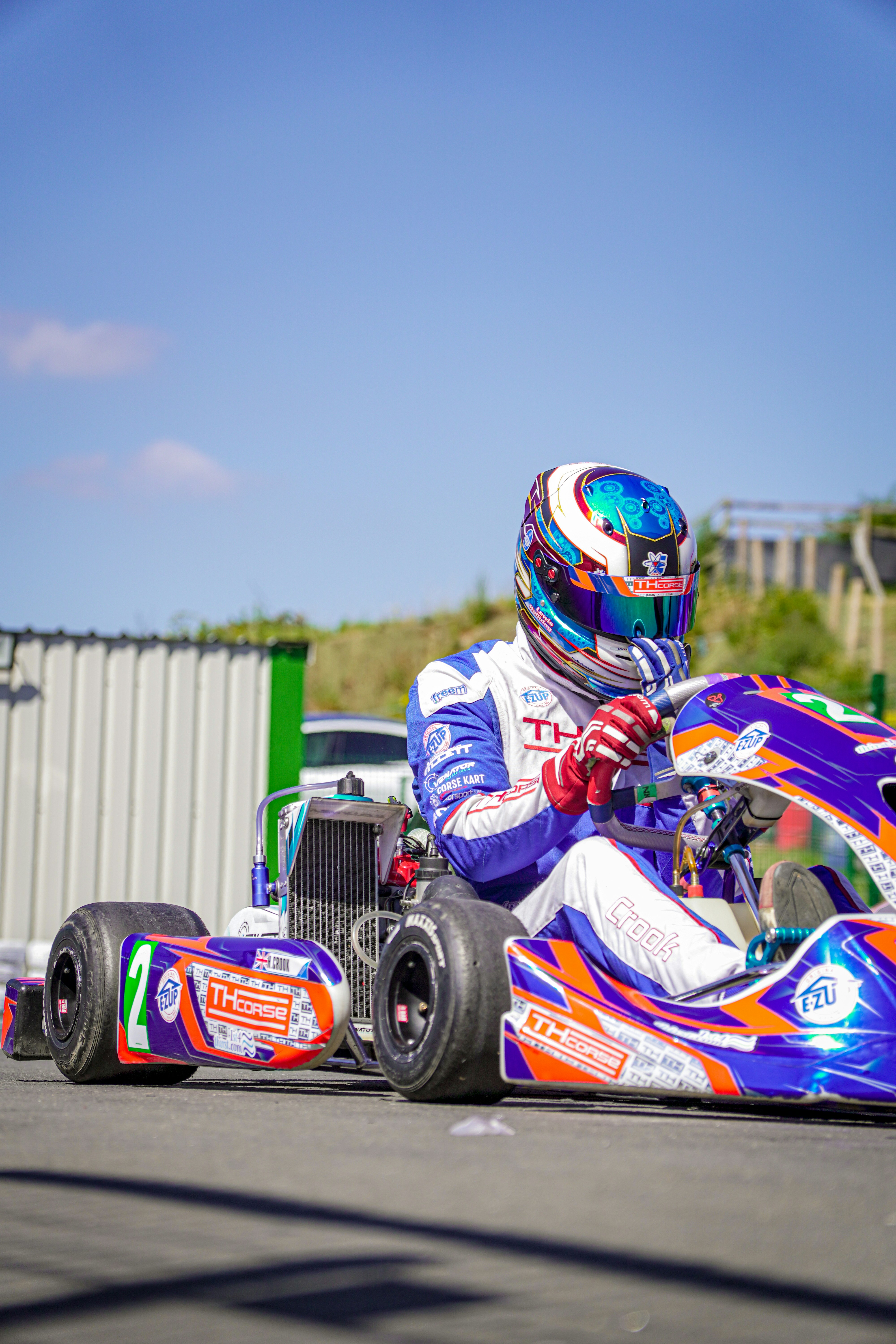 Neon Velocity: Racer and Purple-Orange Go-Kart in Sunlit Paddock