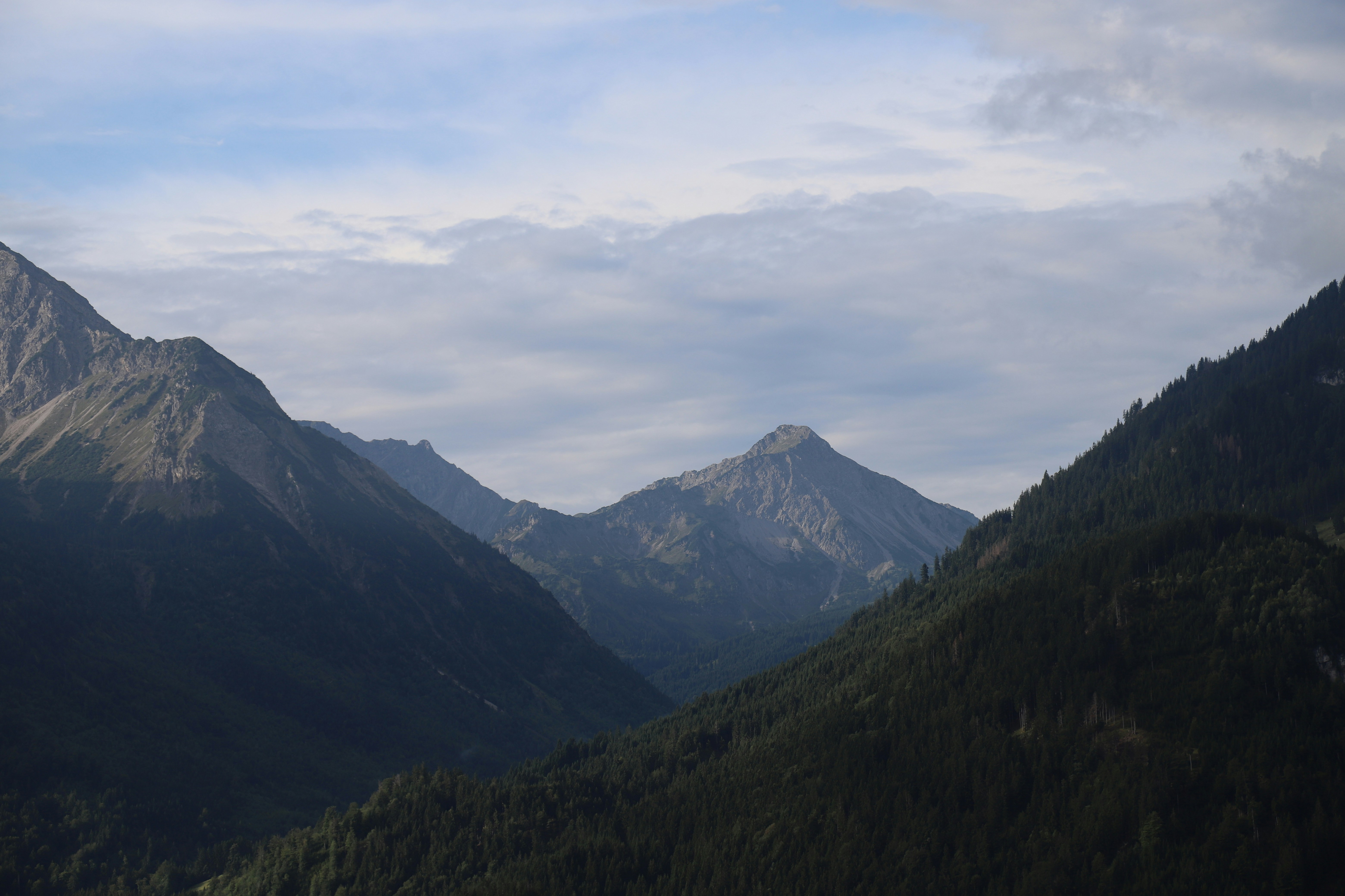 Alpen bei Bad Hindelang | Mountains loom under a cloudy sky.
