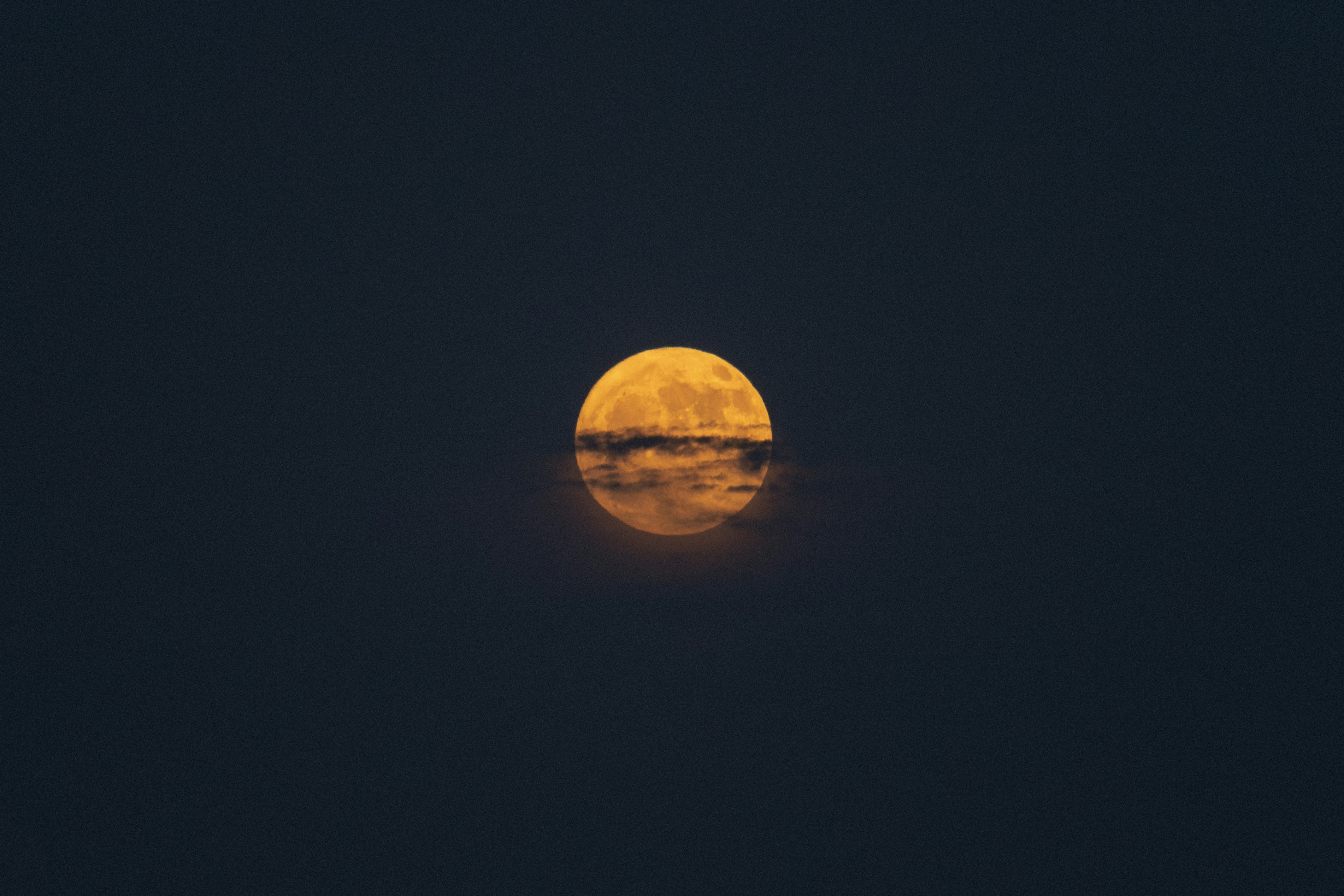 Orange Moon Through Night Clouds Over a Calm Sea