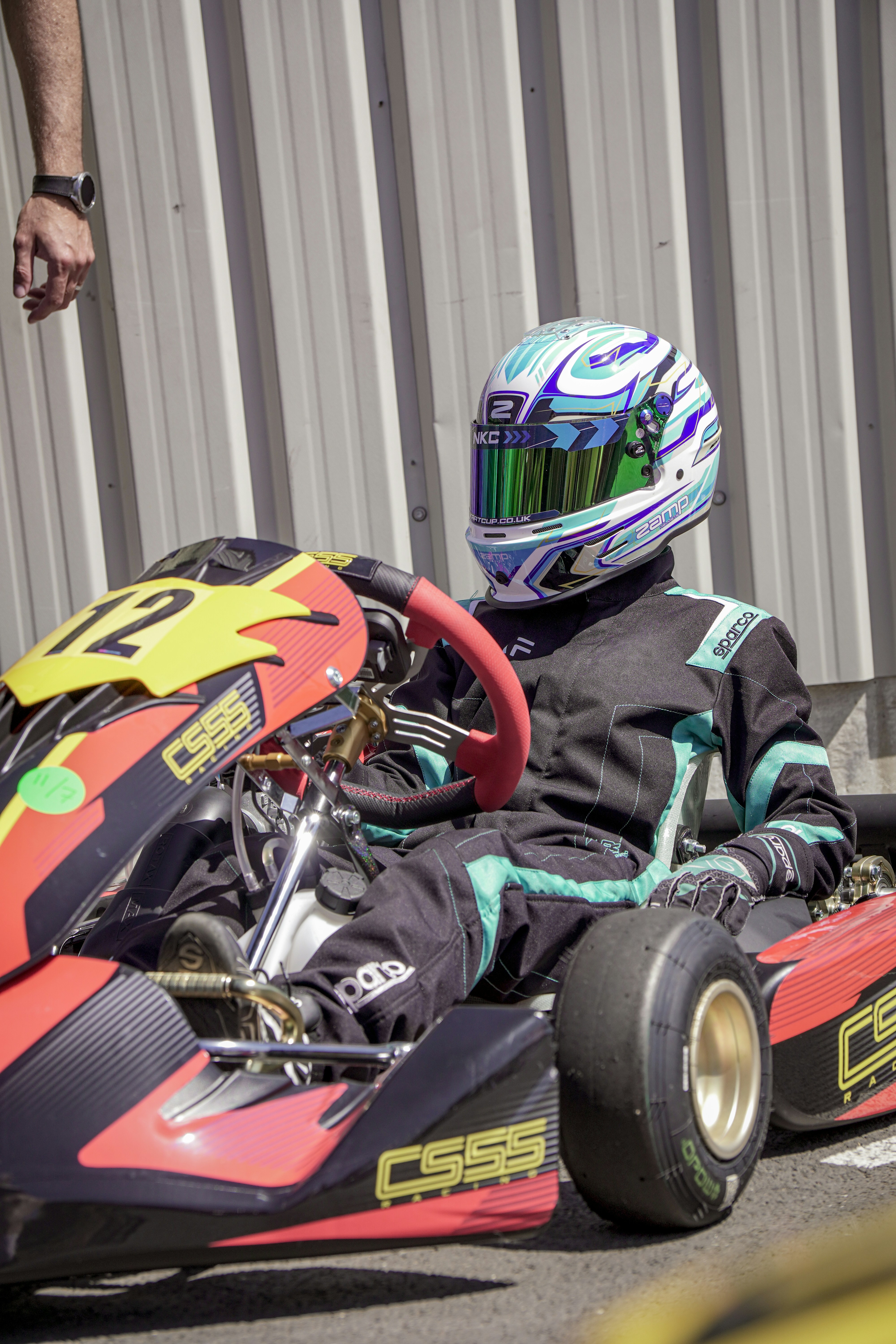 Visor in Focus: Helmeted Racer at the Edge of the Karting Pit