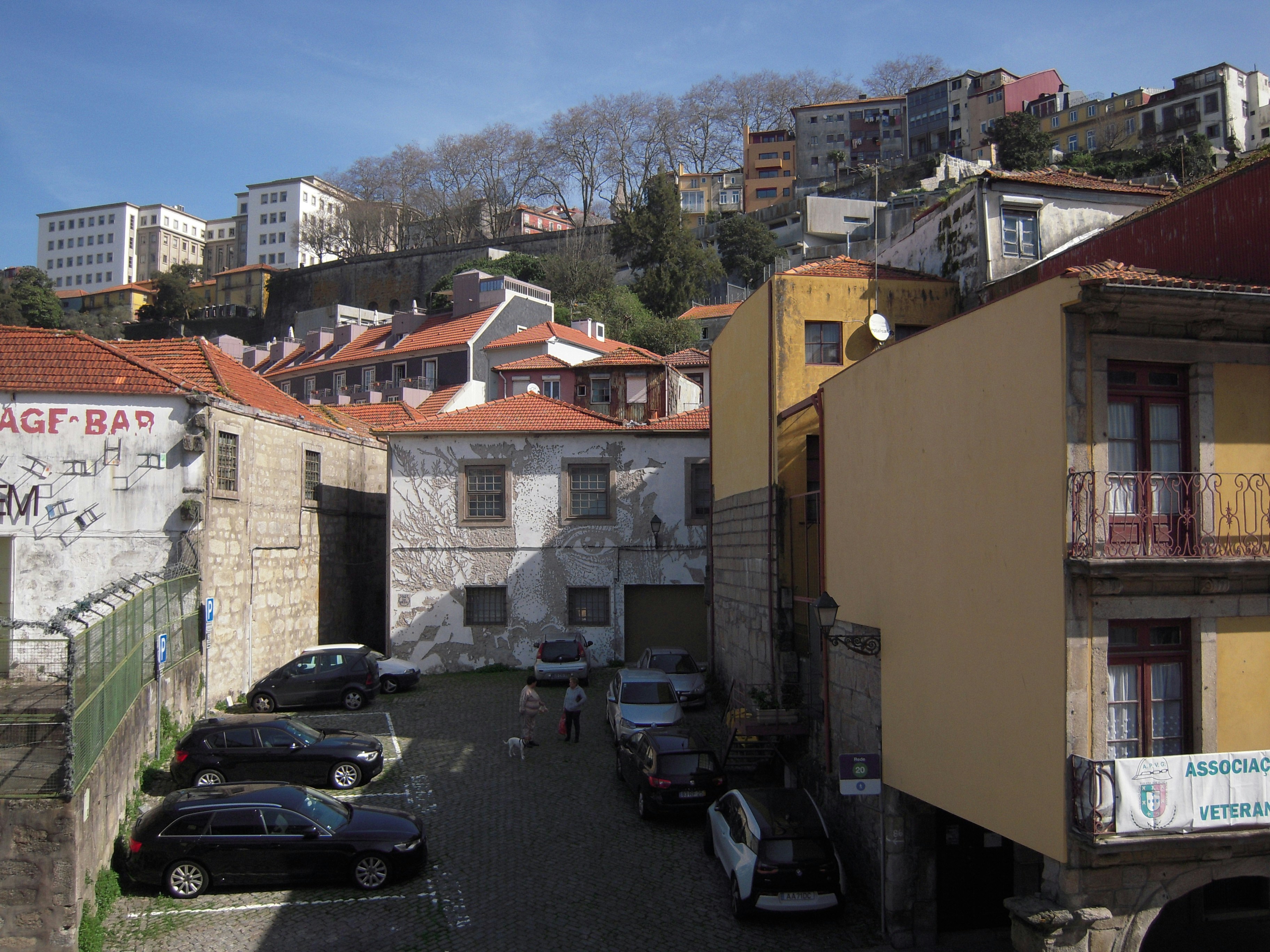 Buildings and parked cars are seen in a city scene.