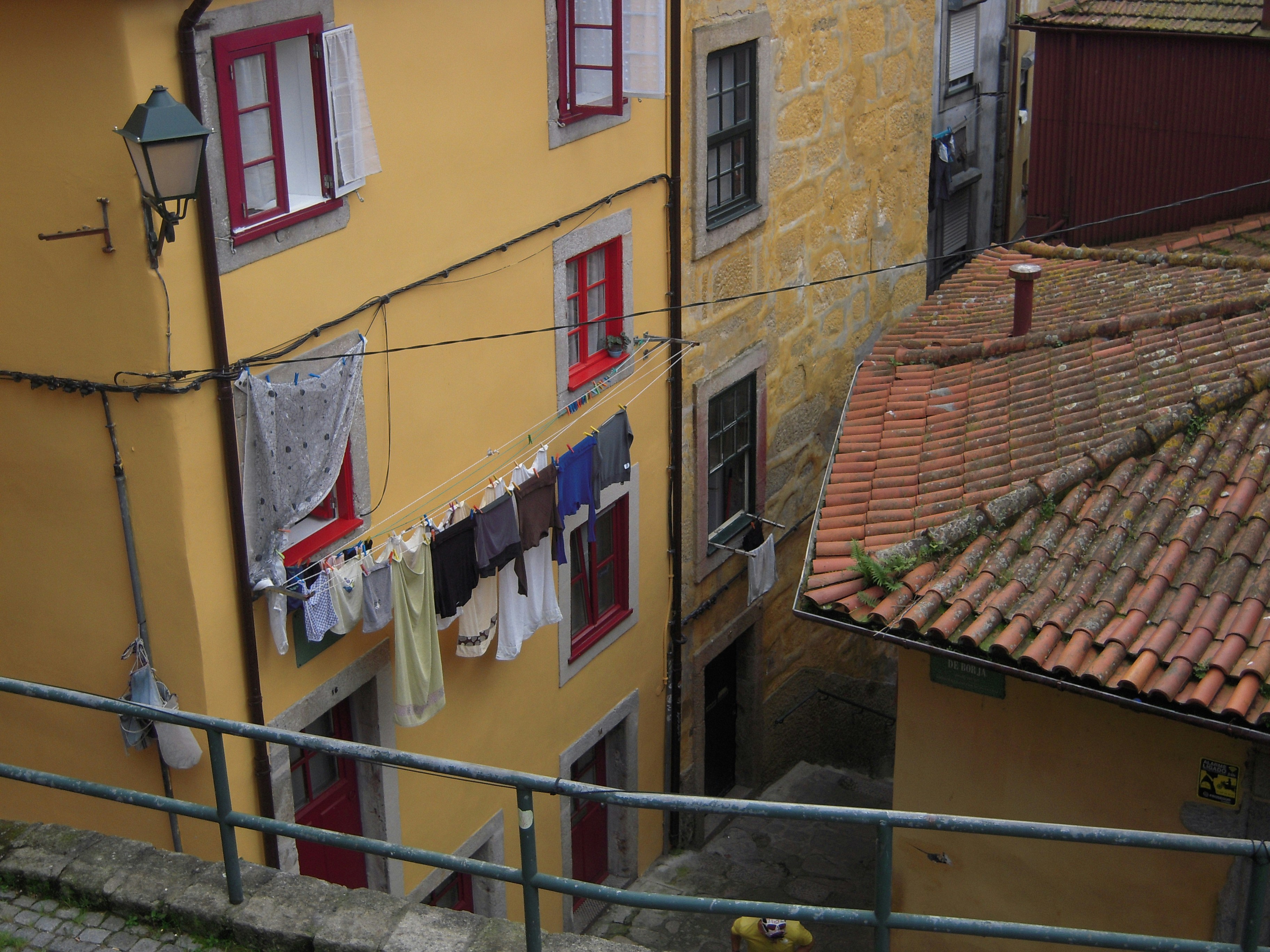 Vibrant yellow buildings adorned with red windows, featuring clothes hanging on a line, showcasing a glimpse of daily life in a quaint neighborhood.