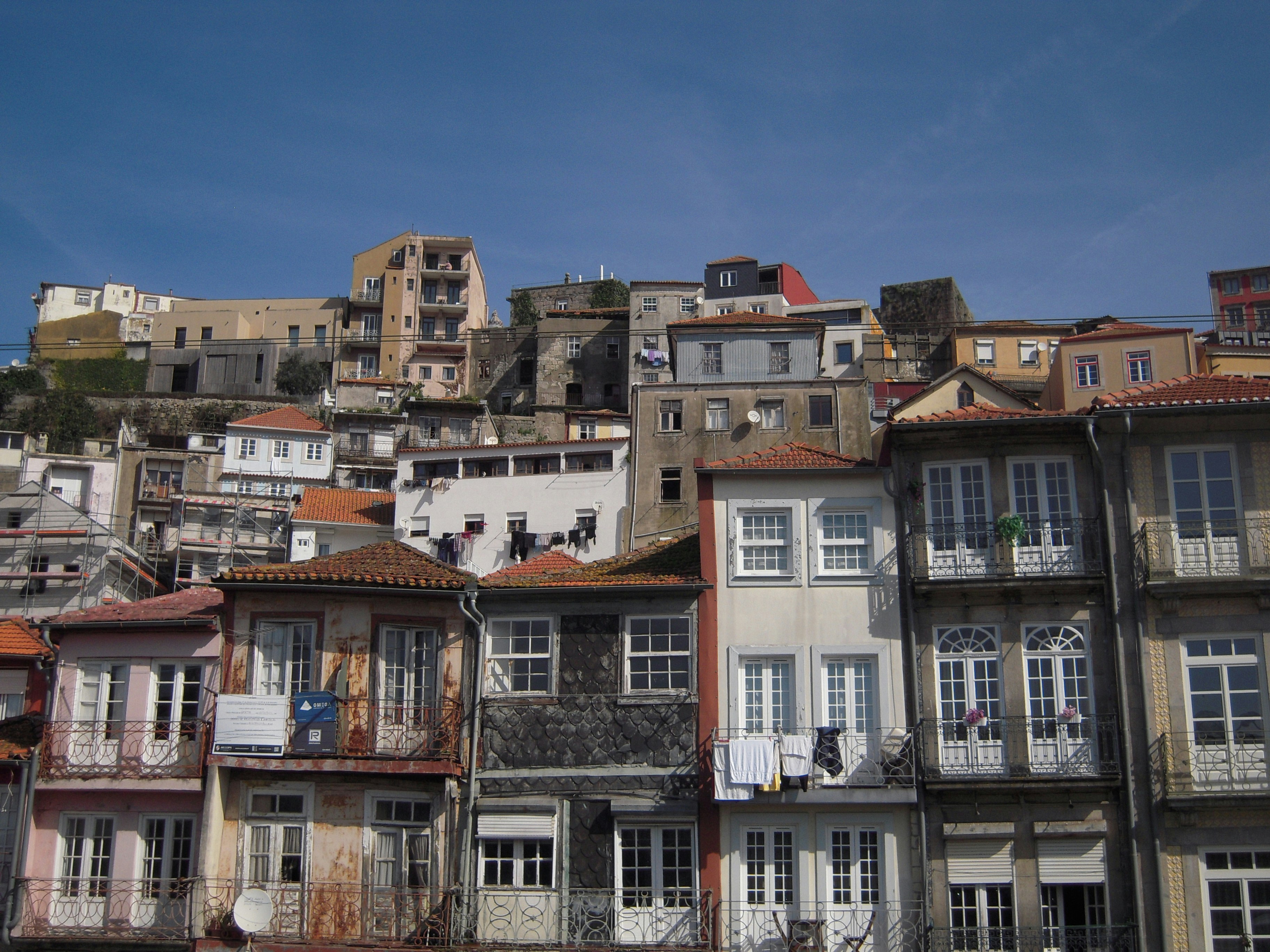Colorful, stacked buildings in a hillside neighborhood showcase a blend of architectural styles and daily life in a vibrant urban setting.