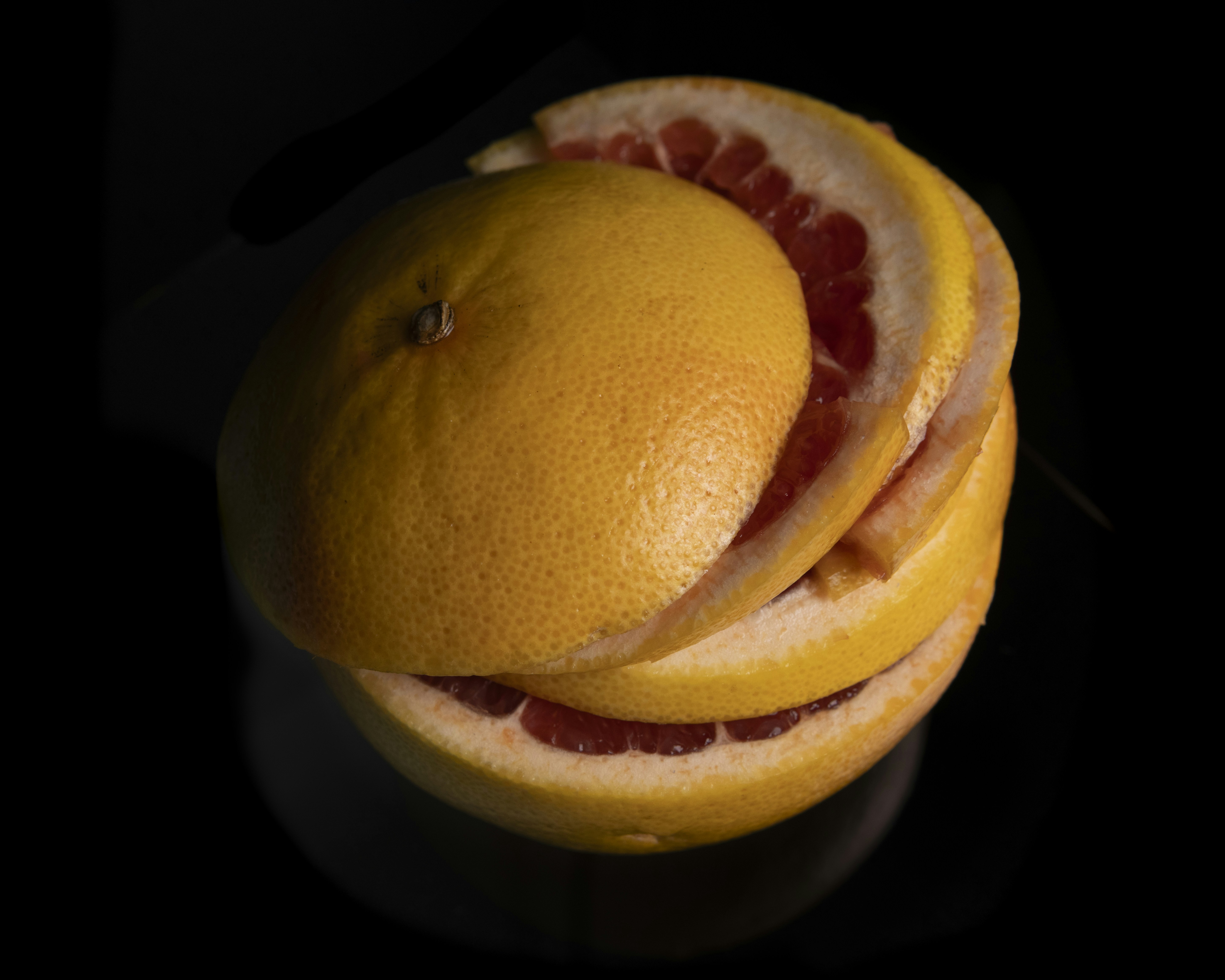 A grapefruit sliced, layered, and isolated on black.
